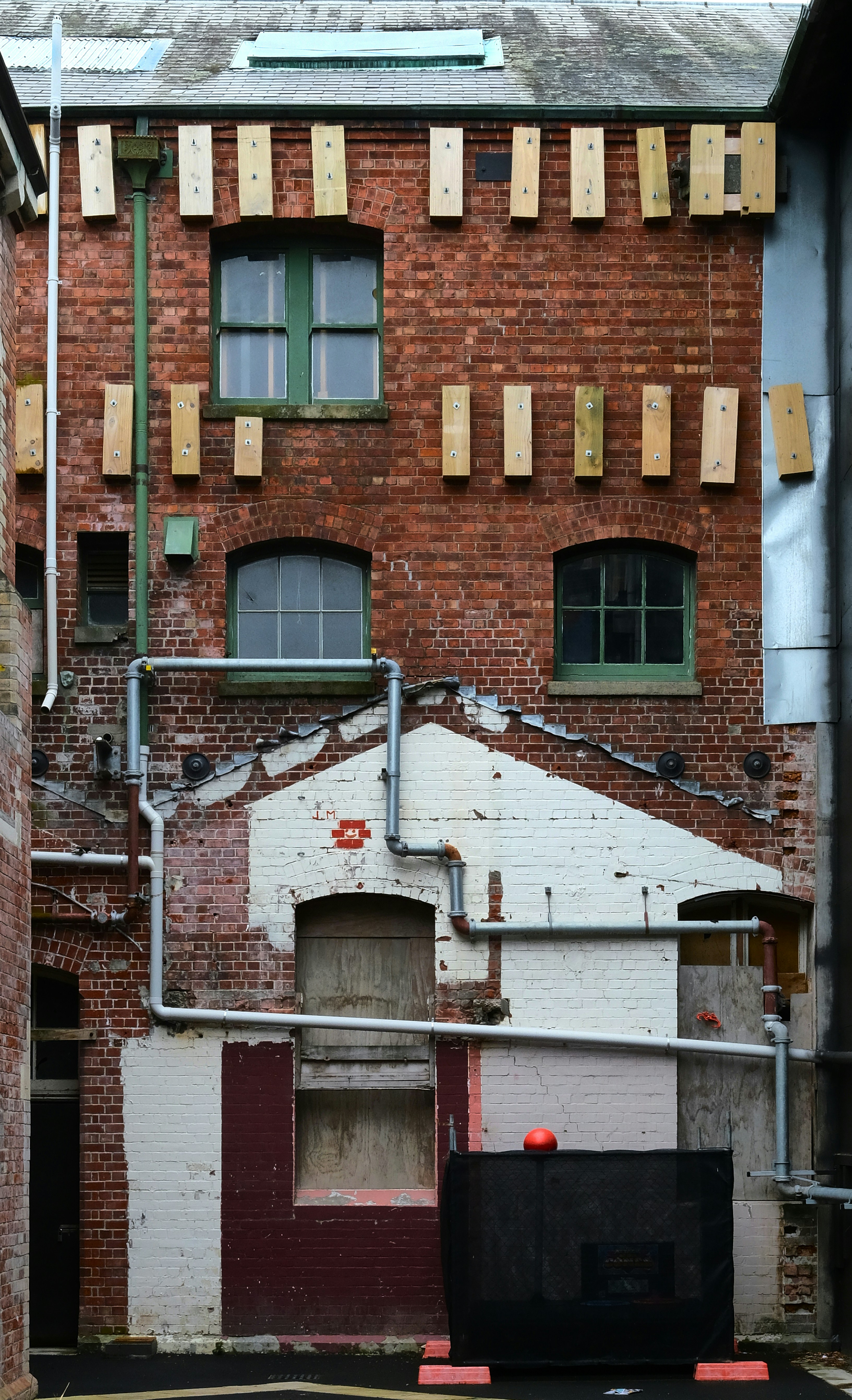 Brickwork and Pipes: An Industrial Facade with Timber Shutters