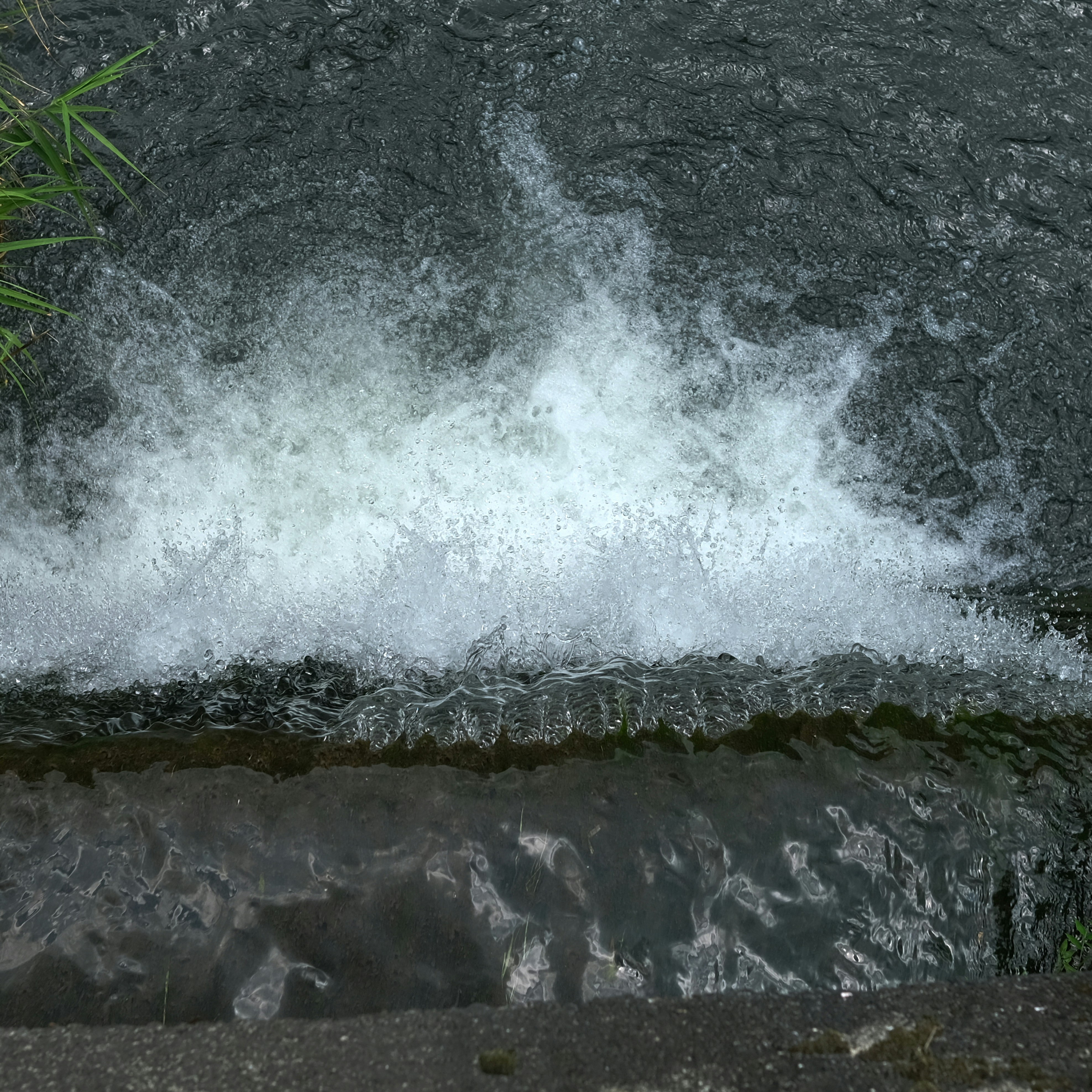 Rushing Current at the Edge: Foam and Water Veil Over Concrete Steps