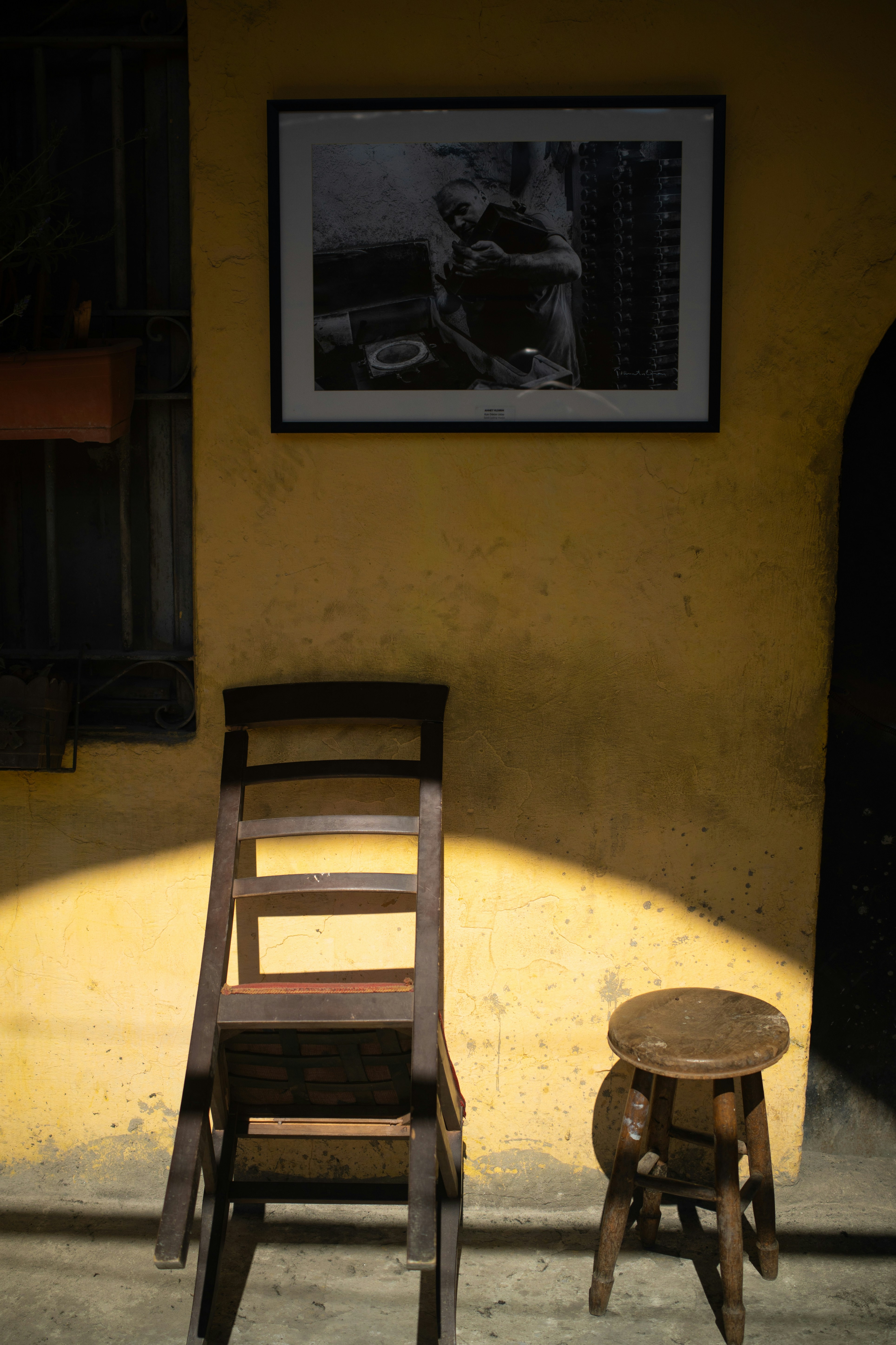 Yellow Wall Spotlight: A Lonely Stool and Framed Portrait