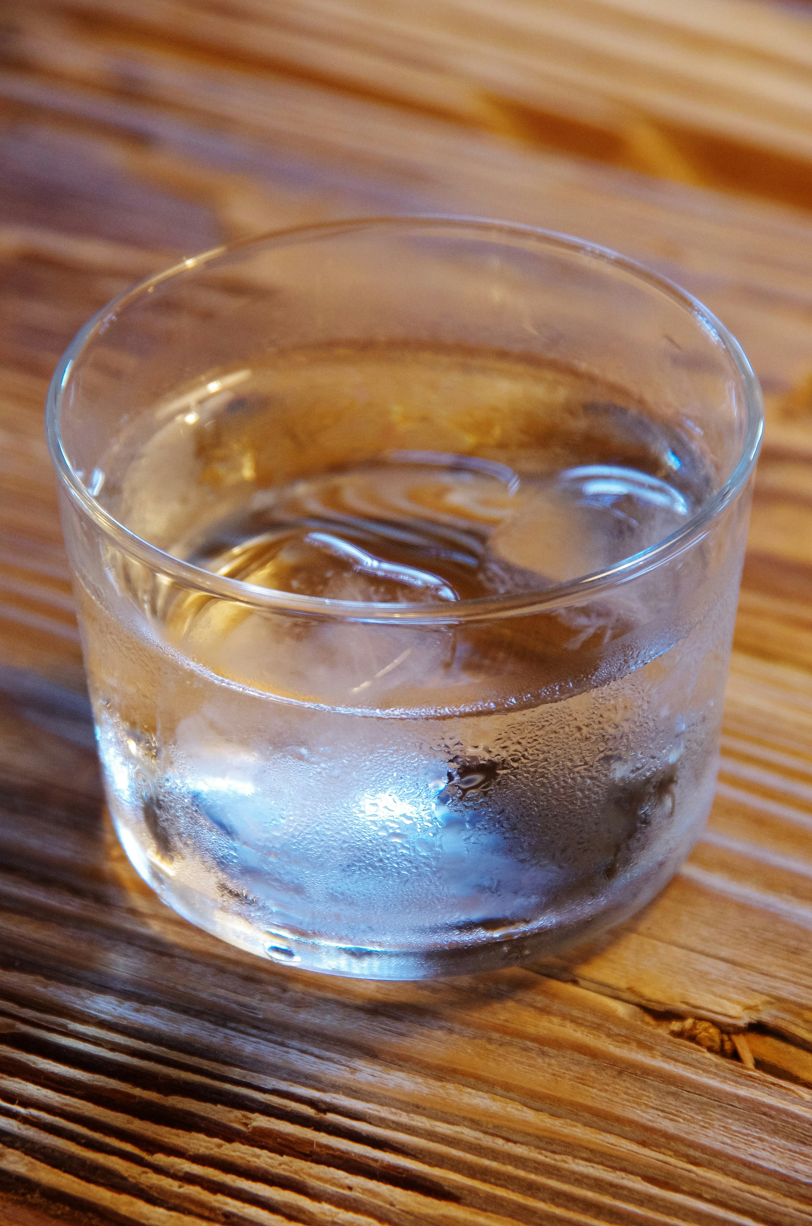 Liquid Prism: A Glass of Ice and Light on Weathered Wood