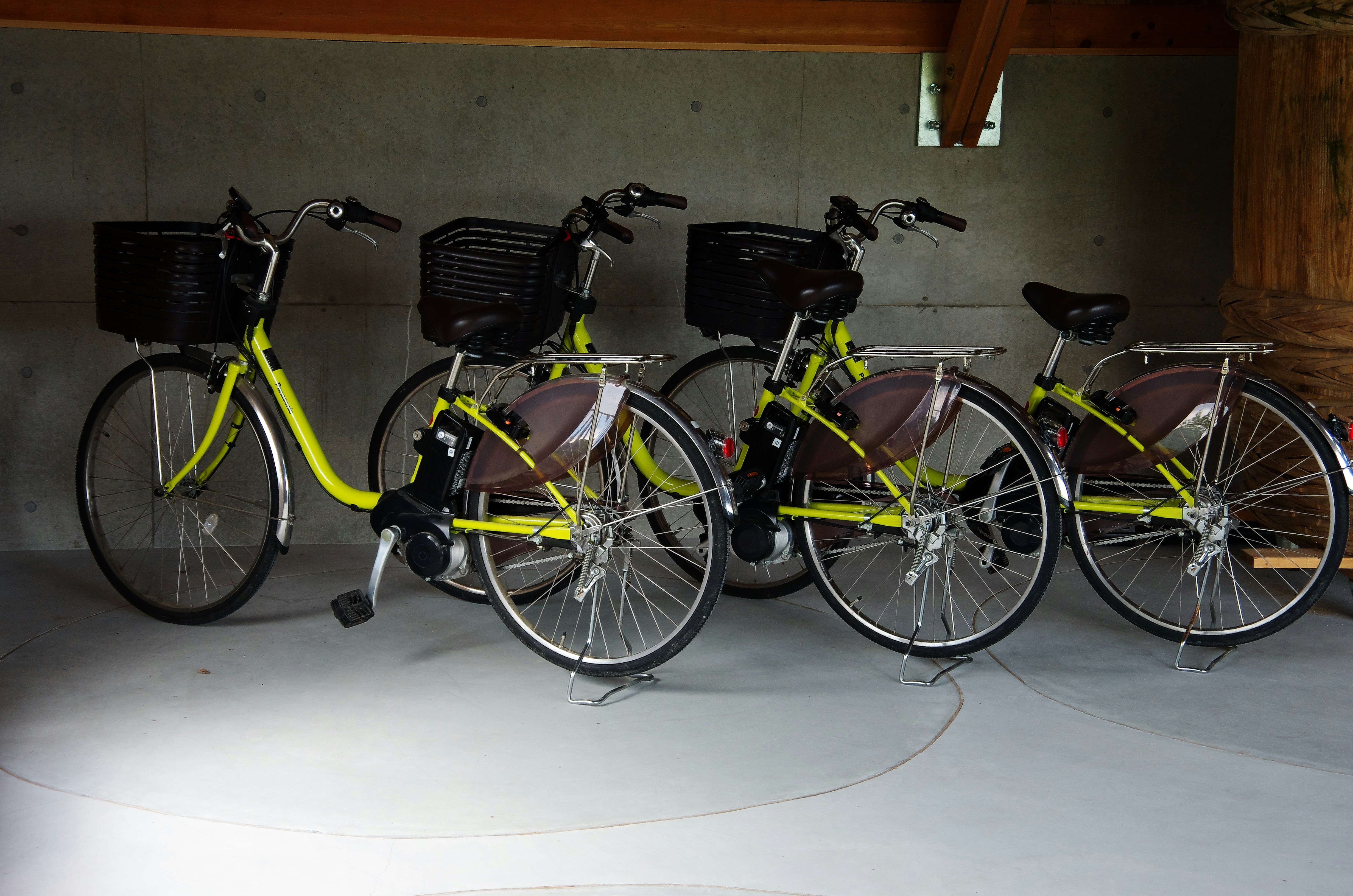 Aligned Cargo: Three Lime Bicycles Resting Under Soft Concrete Light