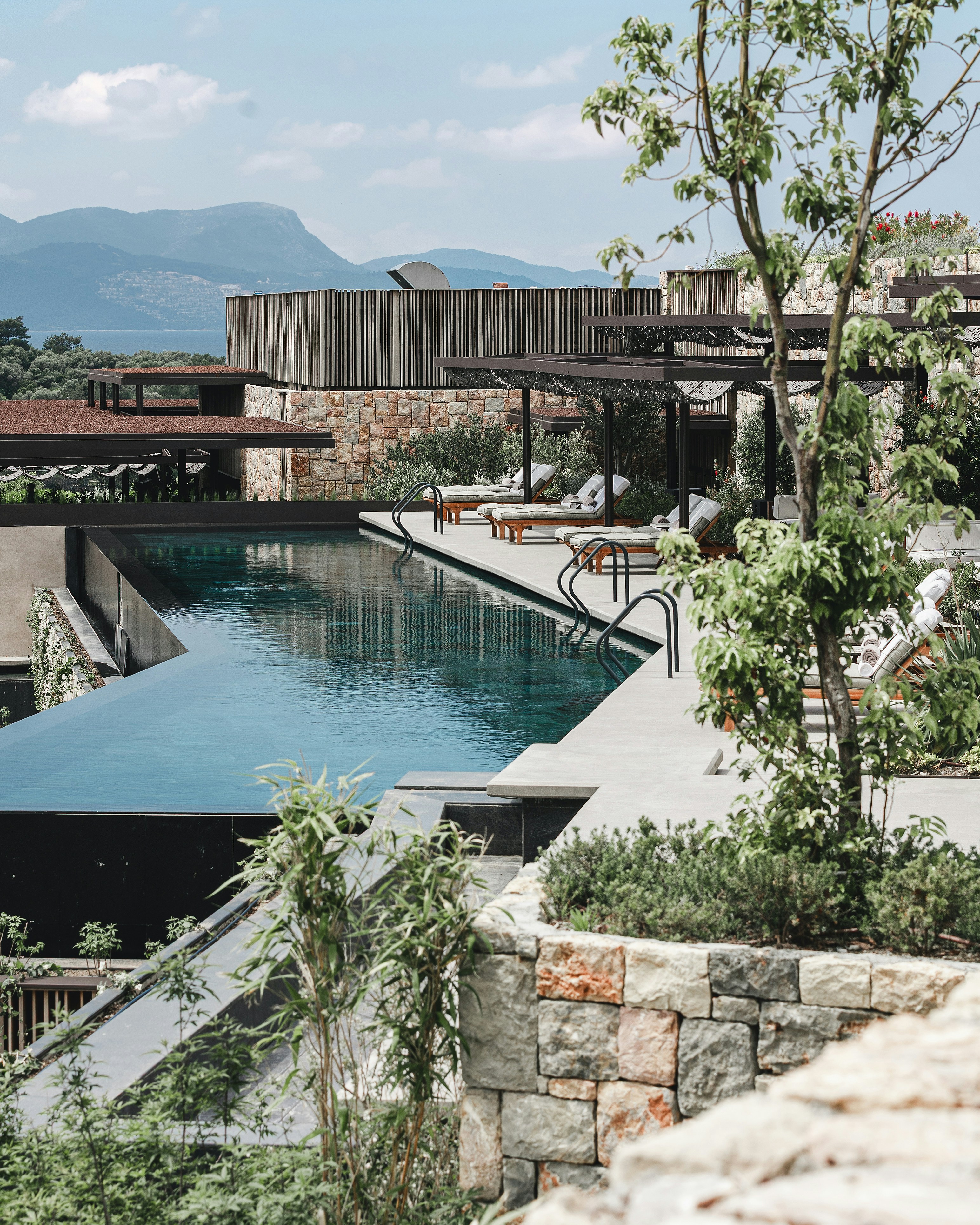 Terraced infinity pool overlooking distant hills and timbered pavilion