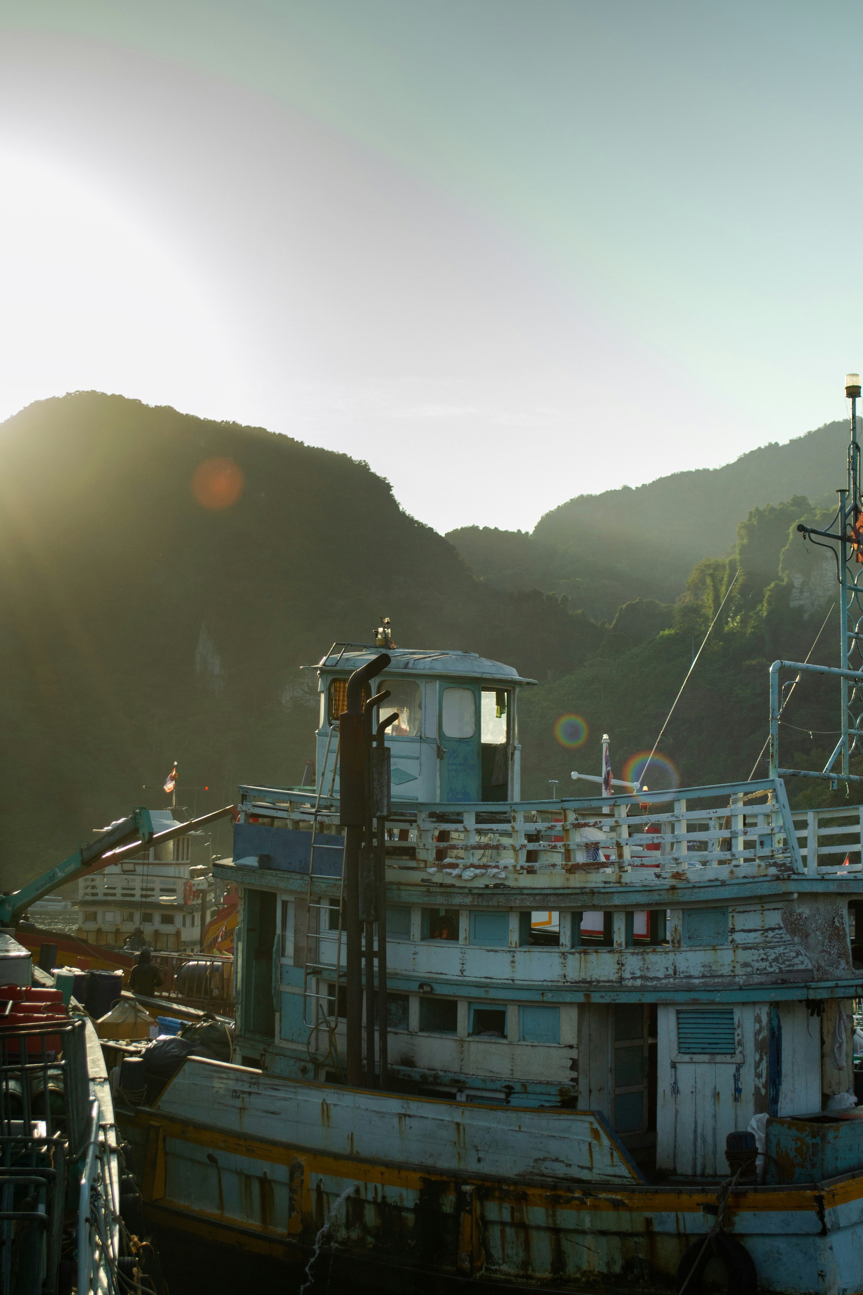 Sunlit harbor: weathered boats under a rising glow