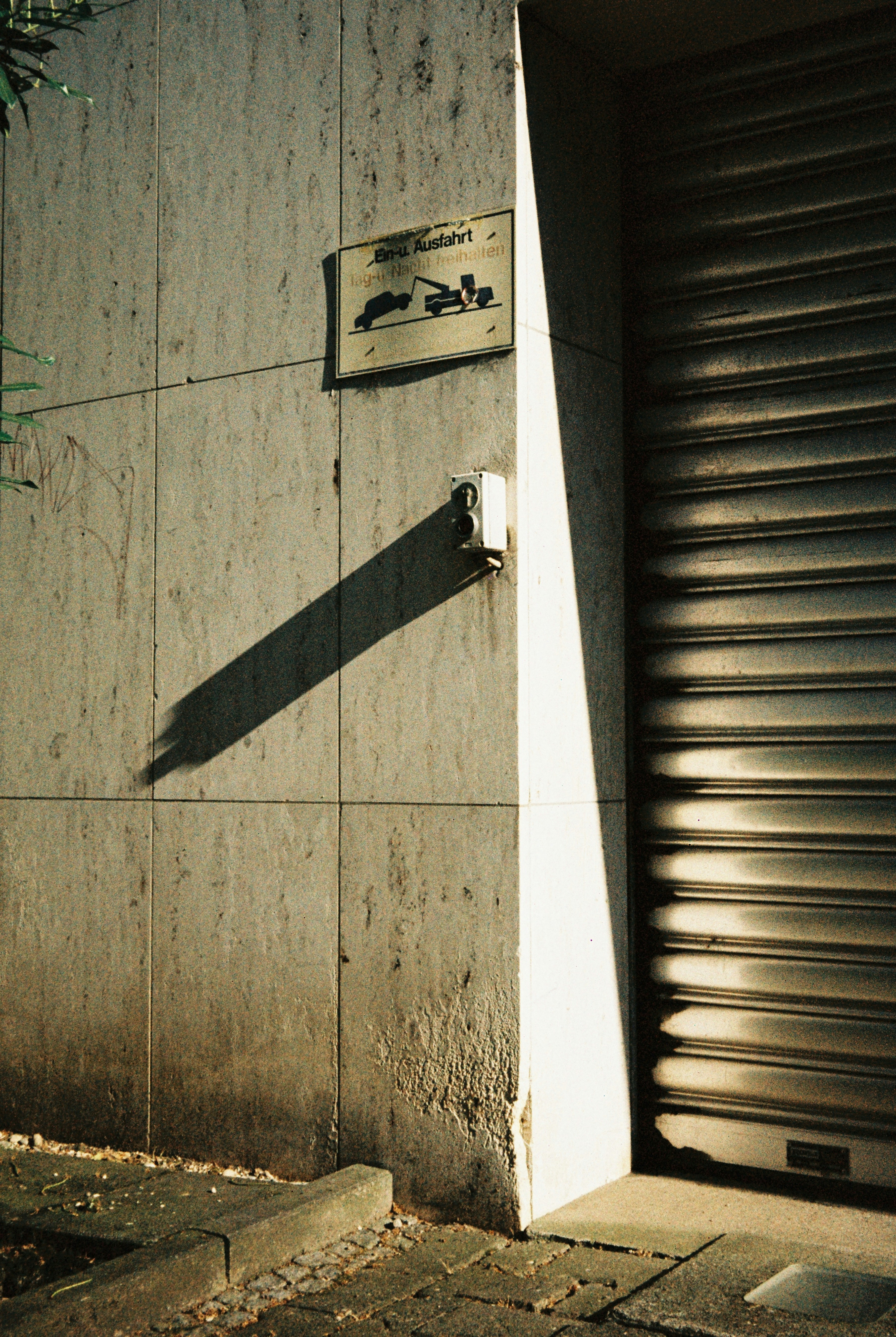 Shadowed Threshold: A Quiet Street Metal Shutter and Sign