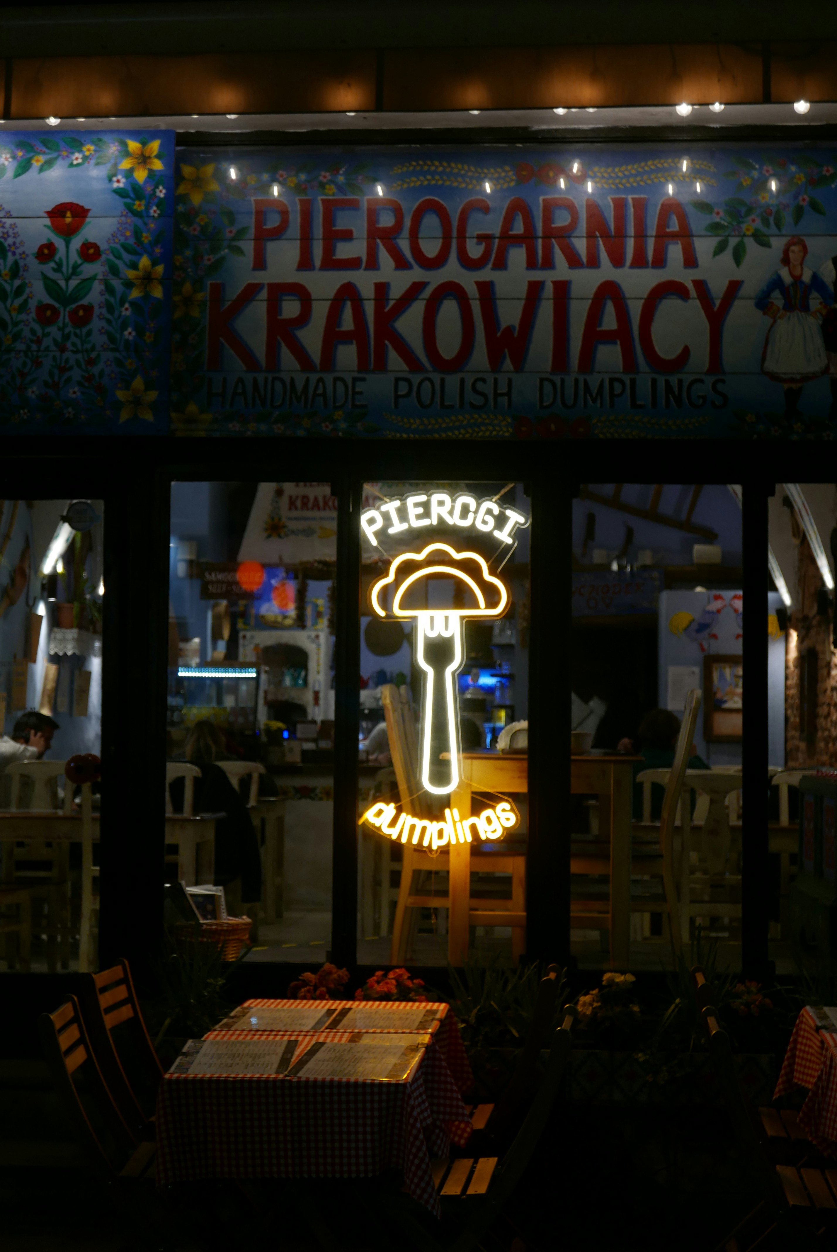 Neon Mushroom Sign Framing a Polish Dumplings Café at Night