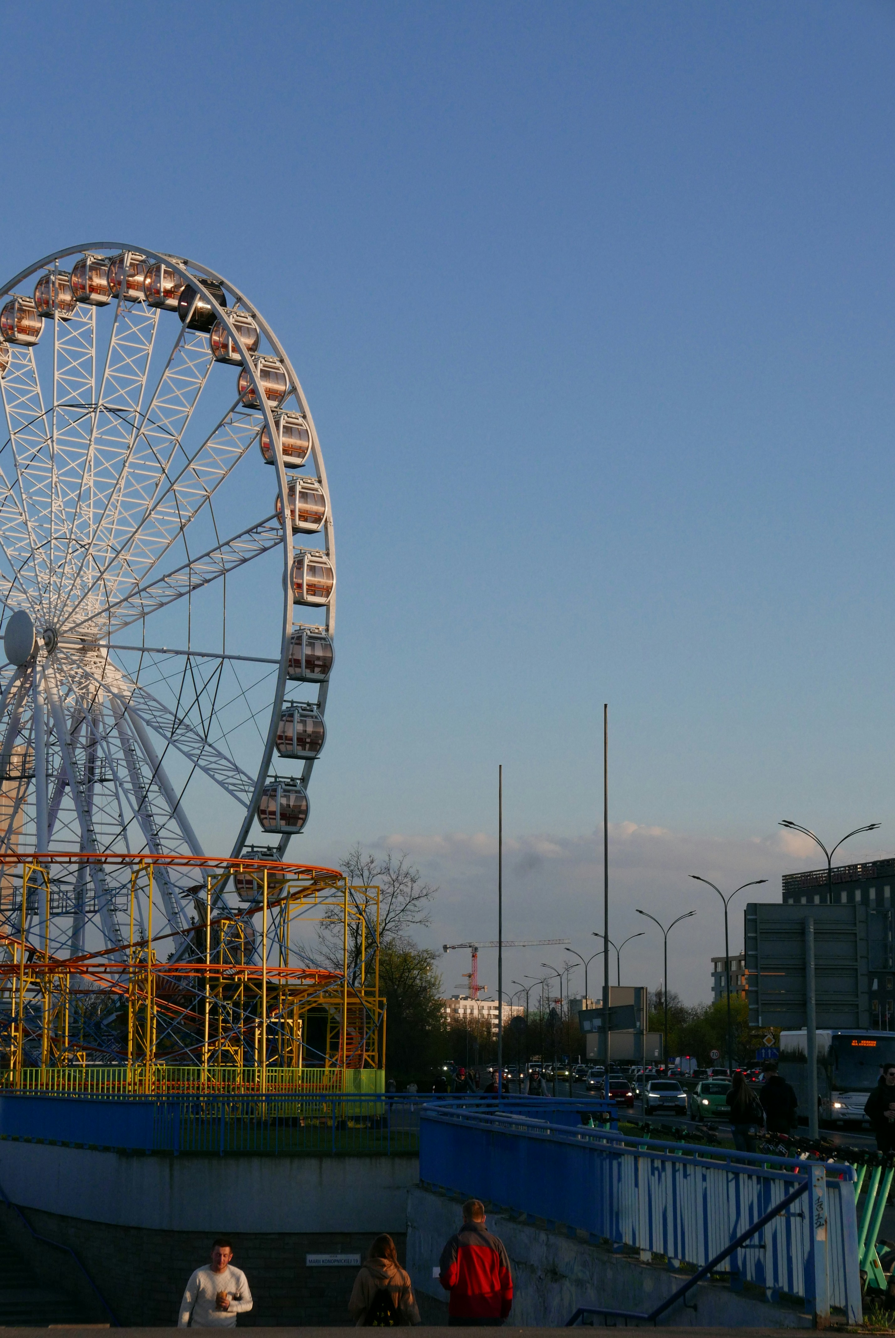 A large ferris wheel and people in a city park.