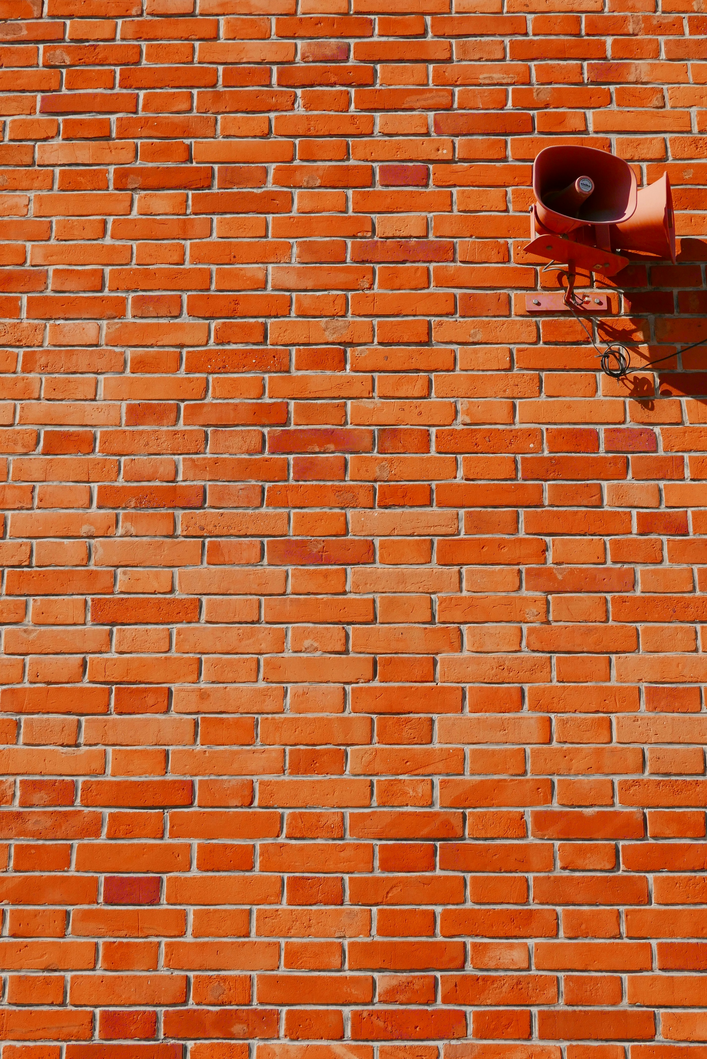 A red brick wall with a speaker mounted on it.