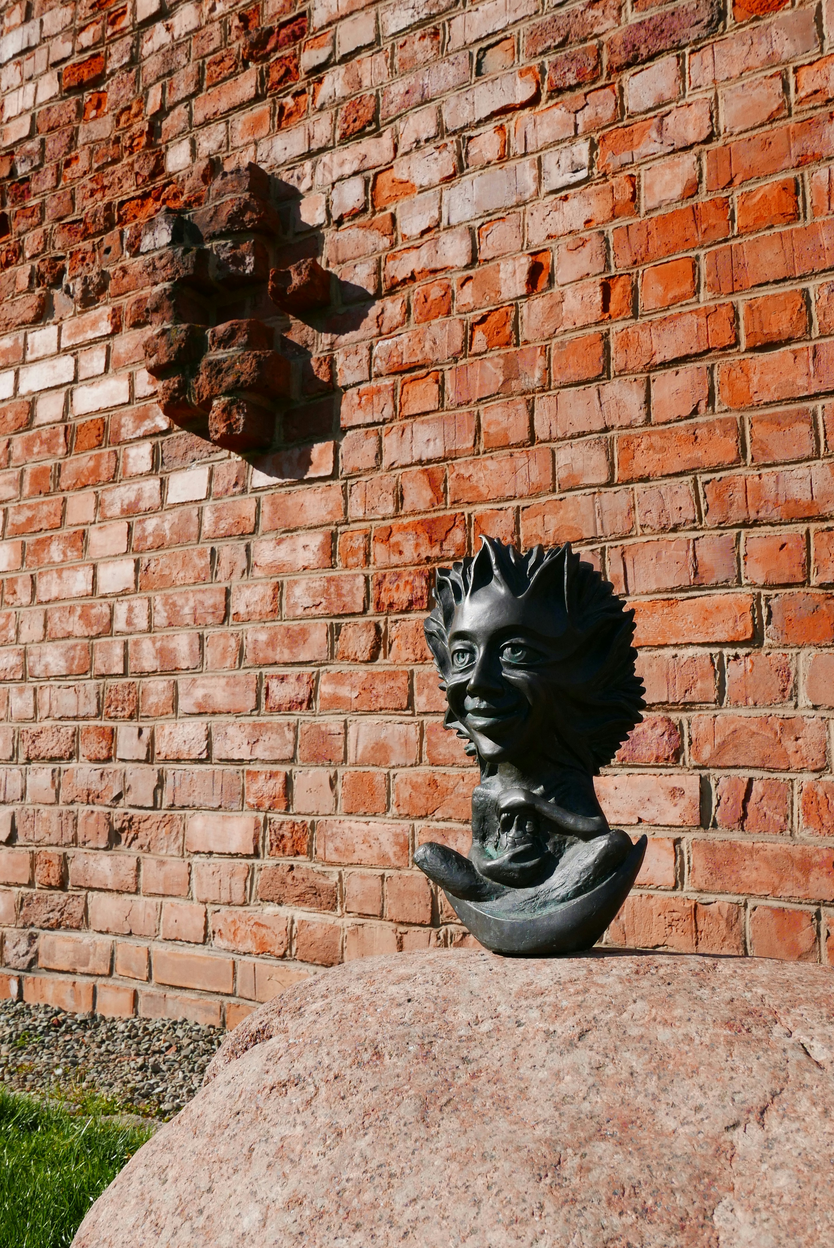 Sunlit Portrait of a Regal Bust Against Red Brick