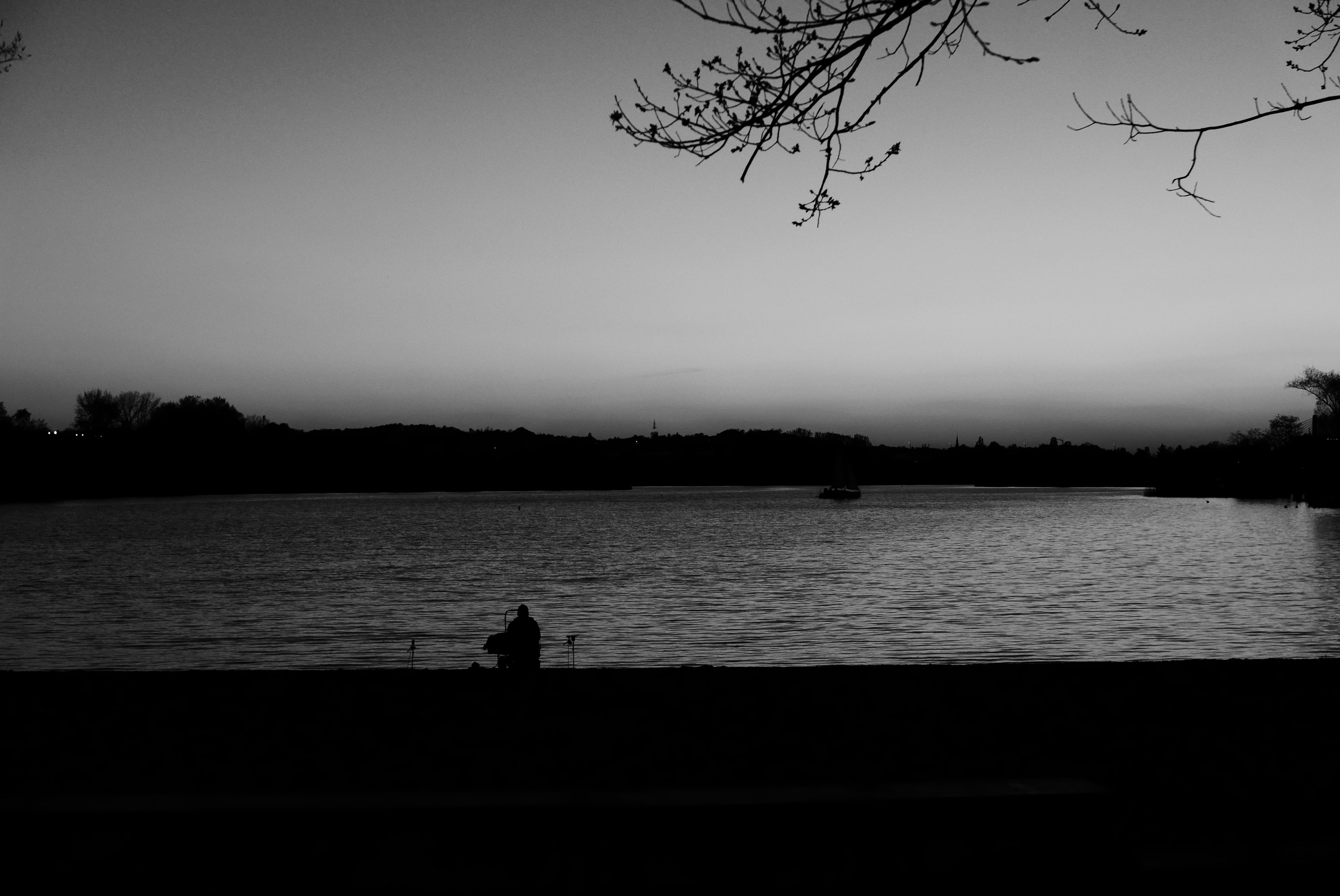 Silhouetted Fisherman at Dusk on a Quiet Riverbank
