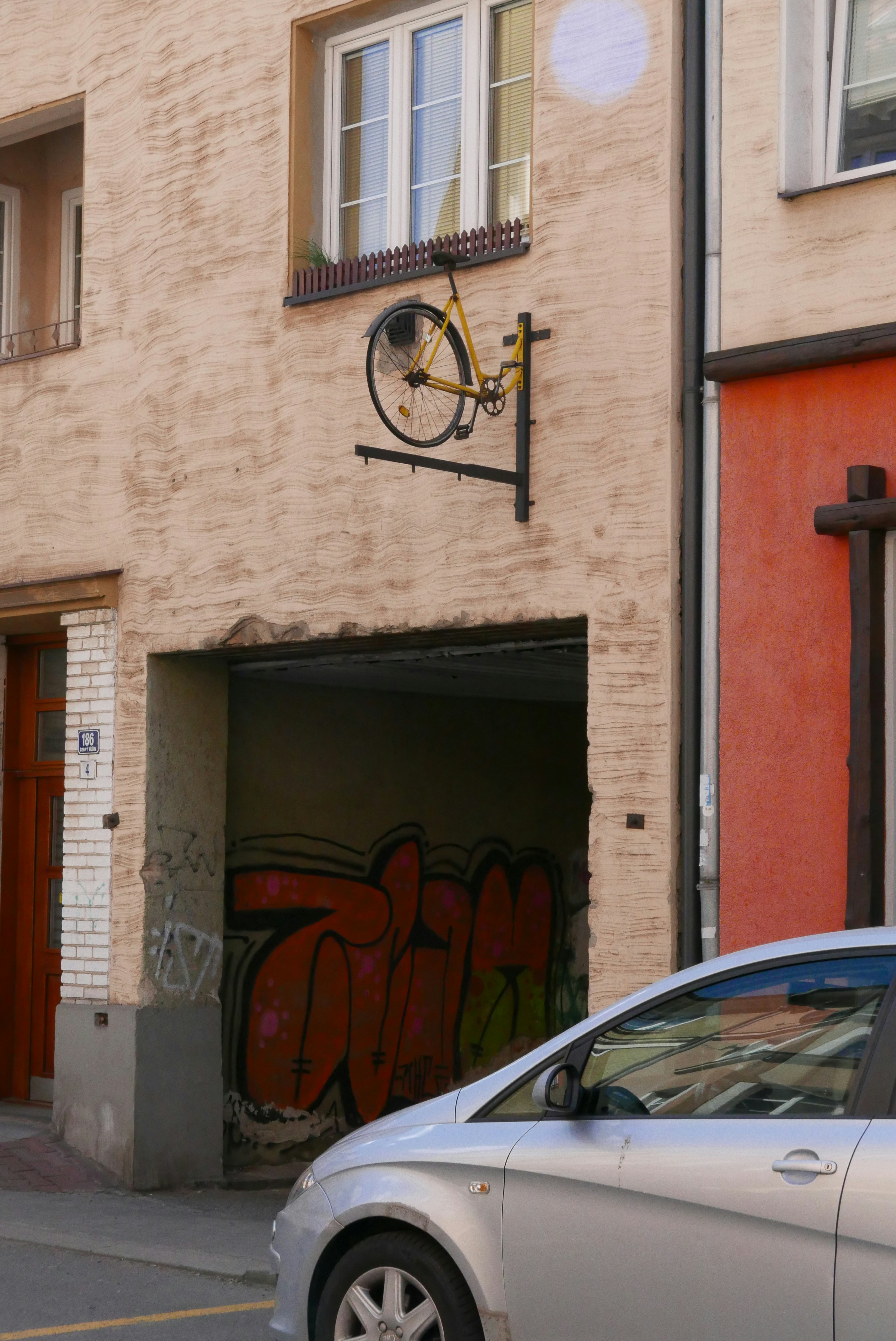 Yellow bicycle mounted on a wall above a graffiti-covered garage door