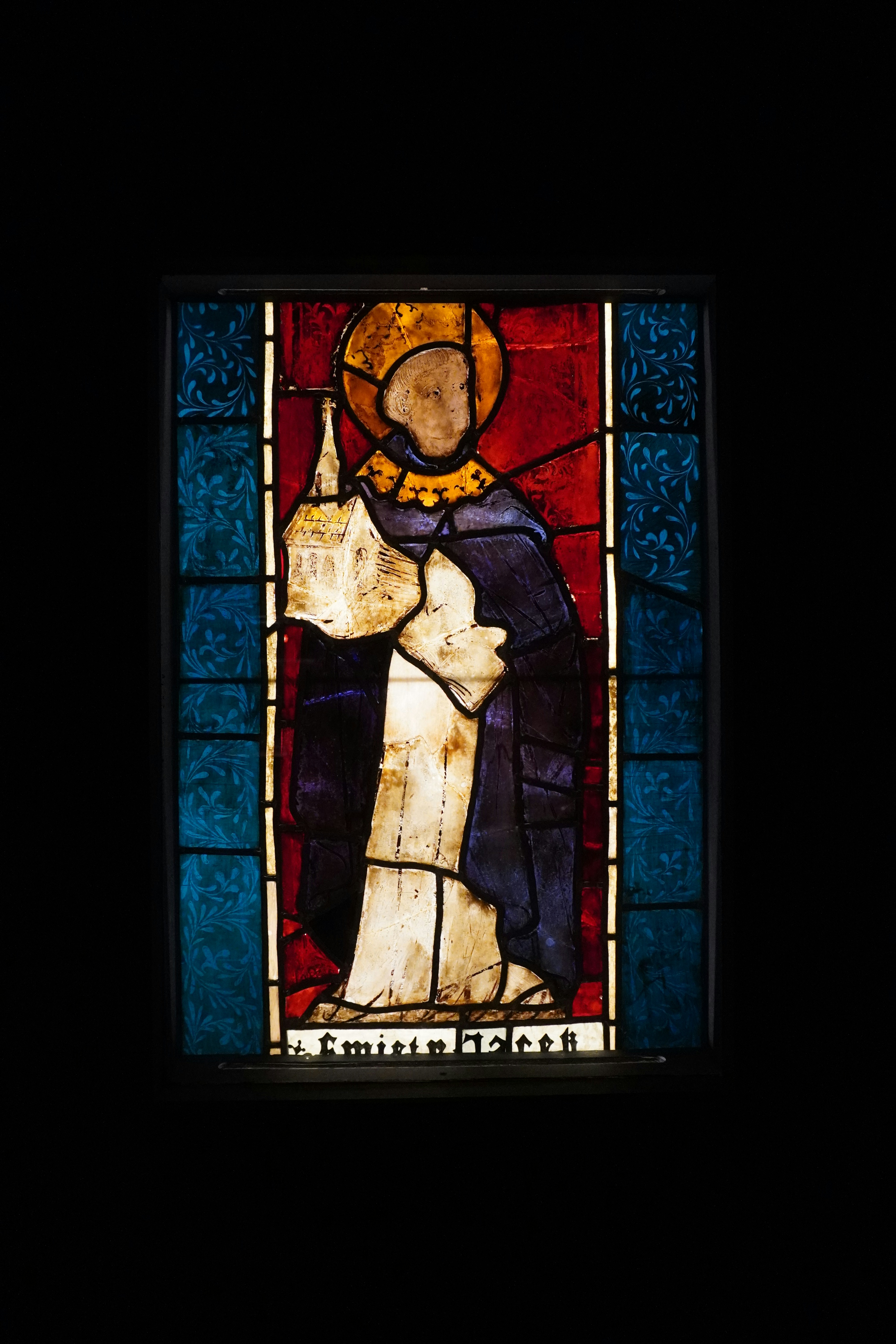 Stained Glass Saint: Silent Figure in a Darkened Chapel