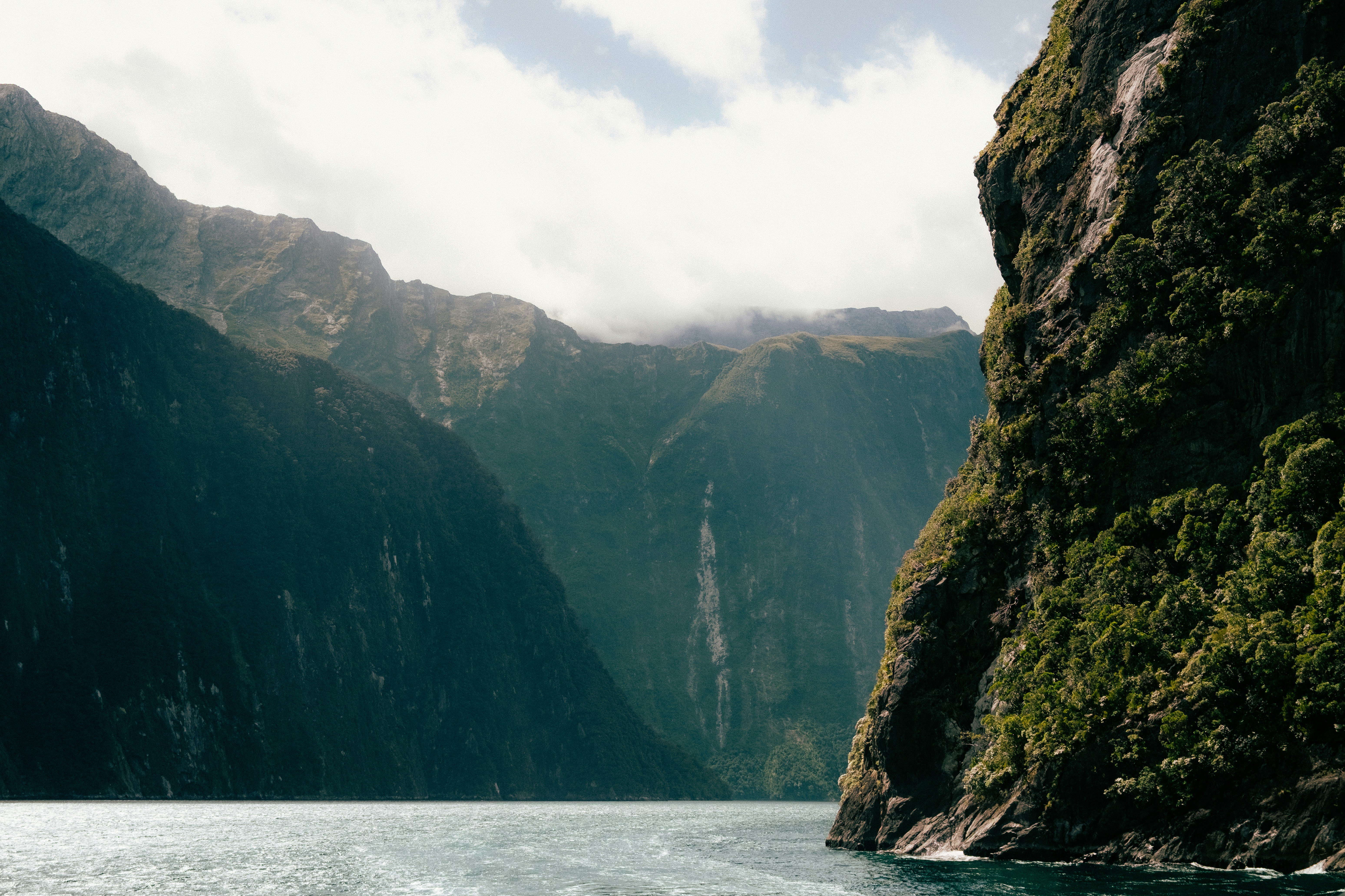 Cliffside Fjord: Sunlit Peak Amidst Coastal Valleys