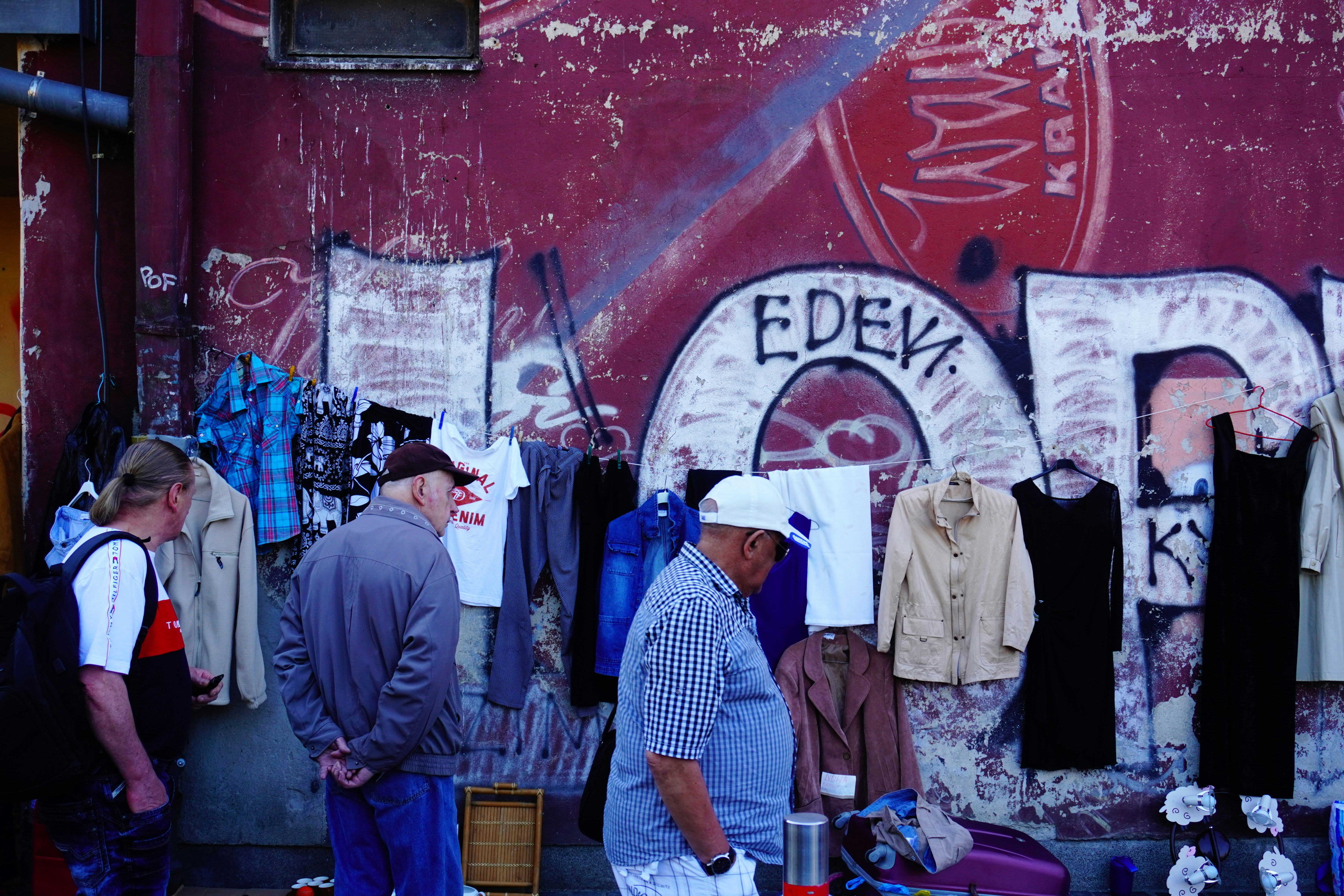 Hanging Clothes and Passersby Against a Graffiti Wall