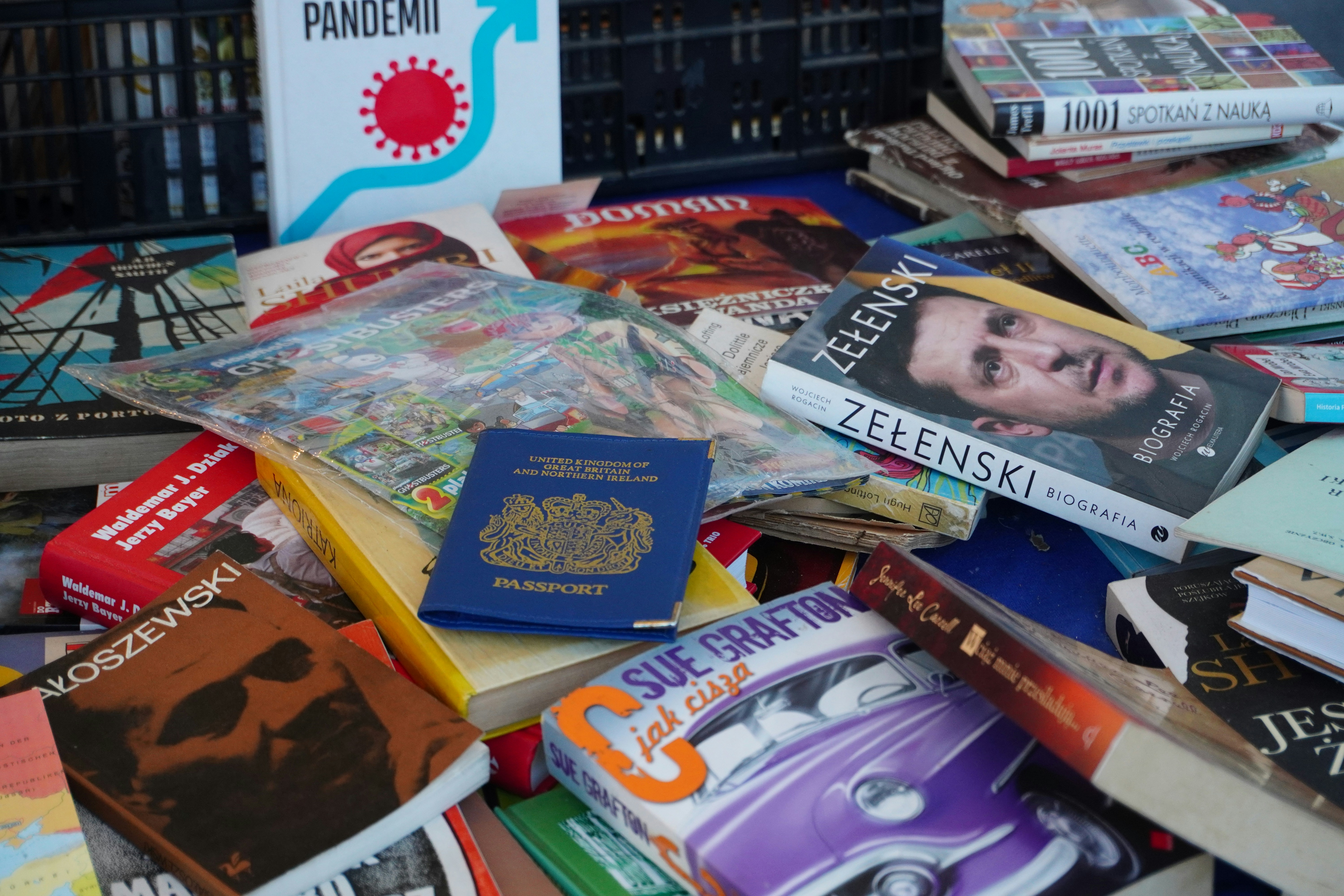 A cluttered pile of various books and a blue passport.