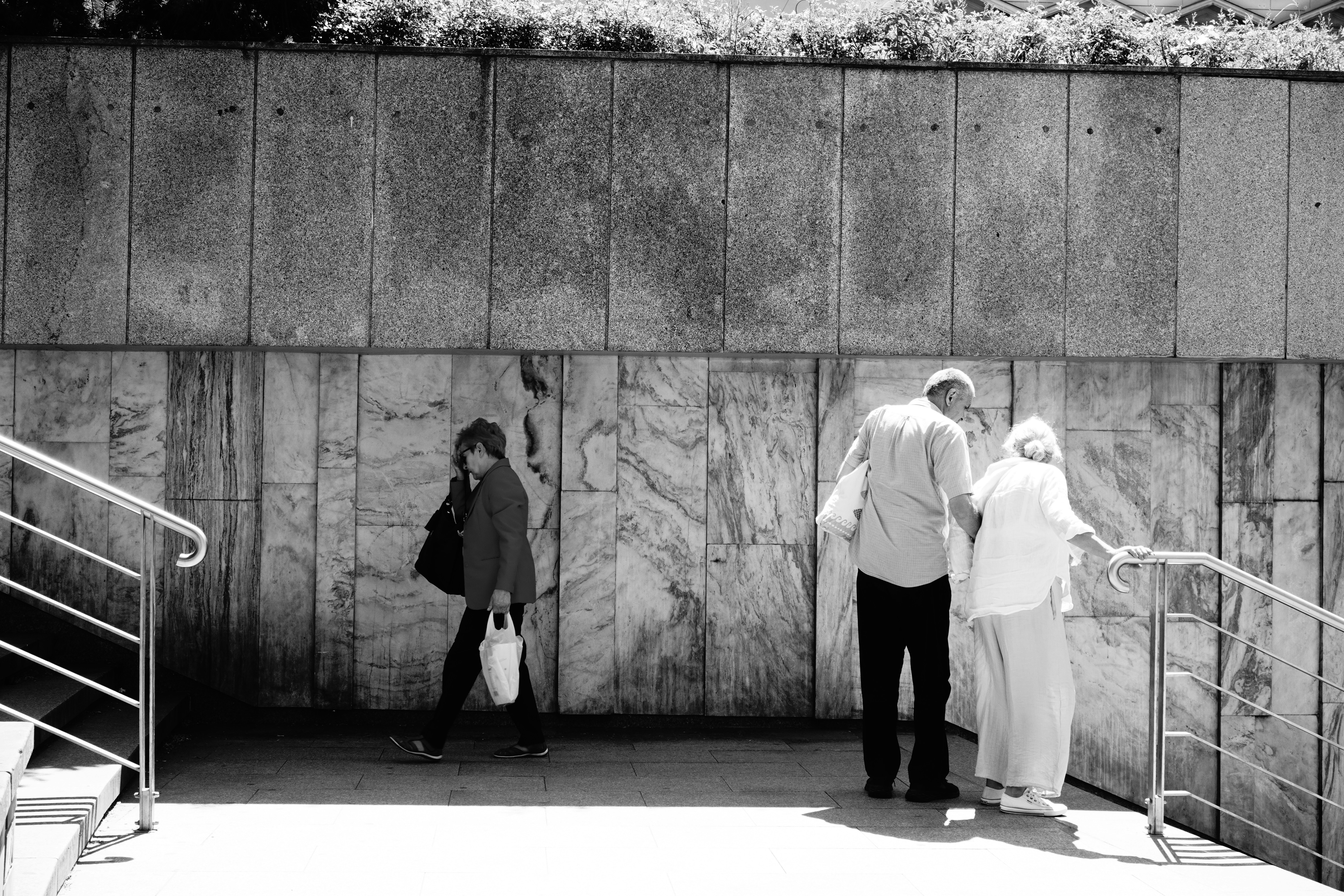Quiet Arc: Strangers in a Sunlit Concrete Corridor