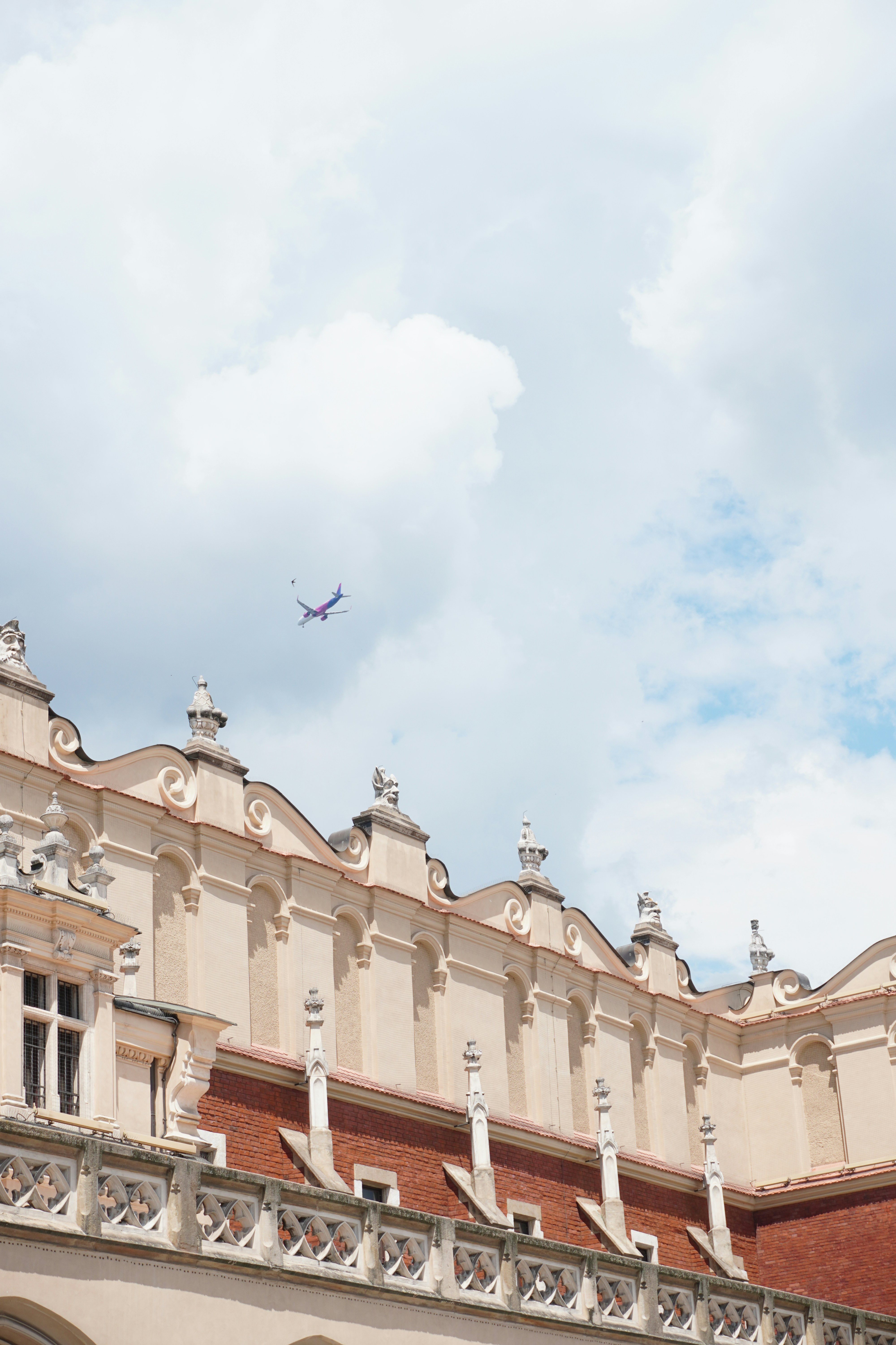 A lone plane crosses an ornate skyline under a bright sky