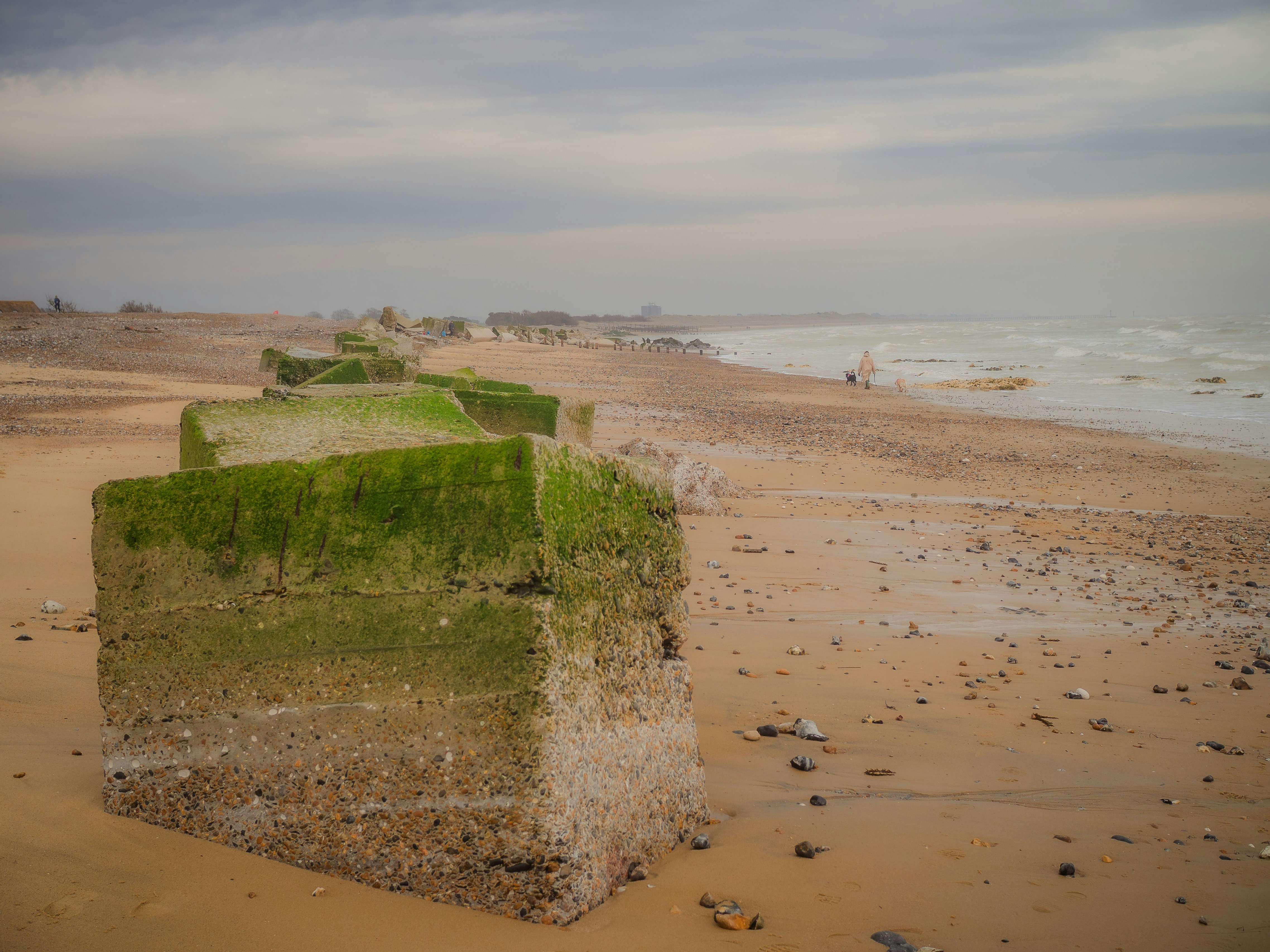 Green-topped seawall pillars marching along a quiet shoreline