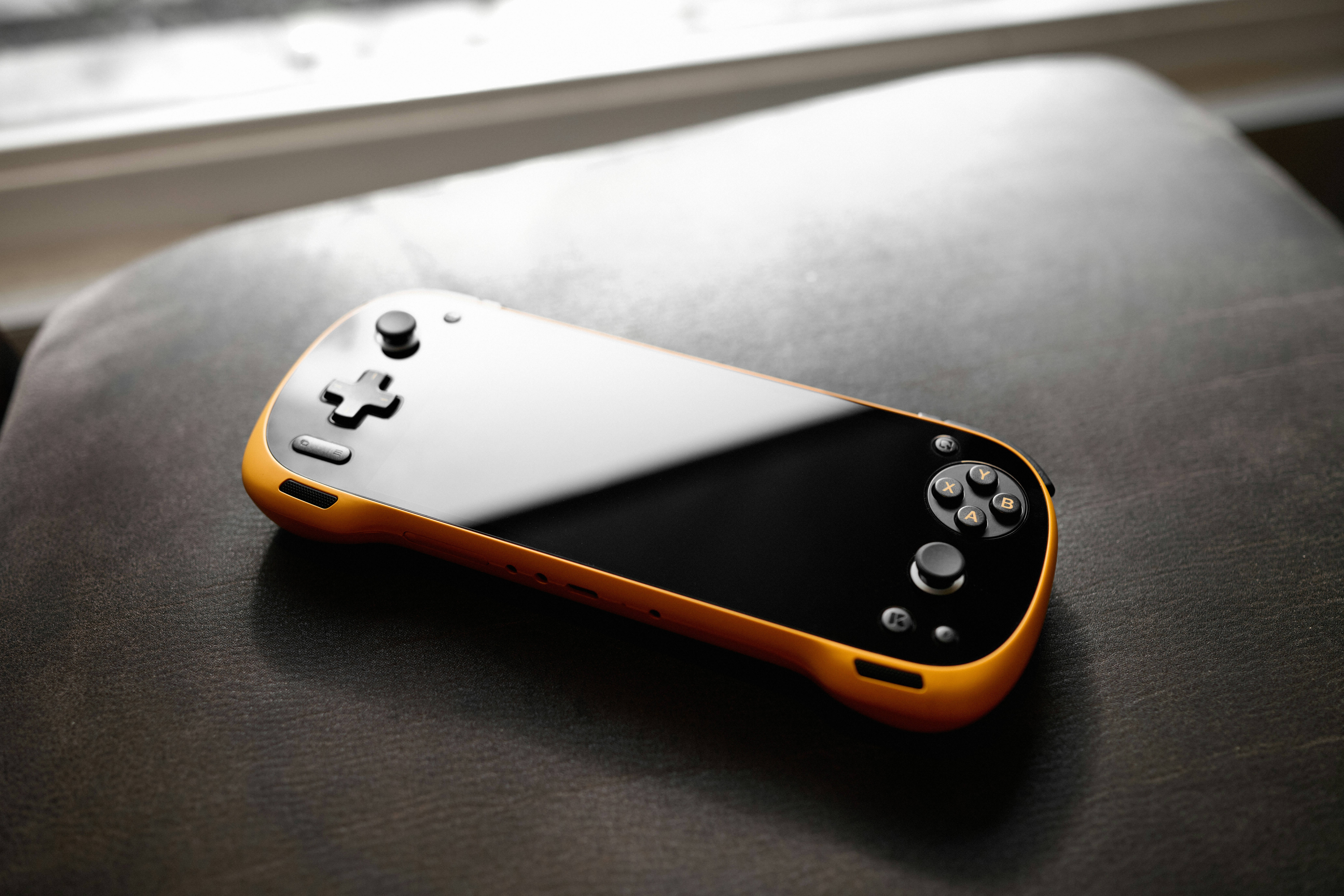 Orange-Edged handheld console resting on a dark surface