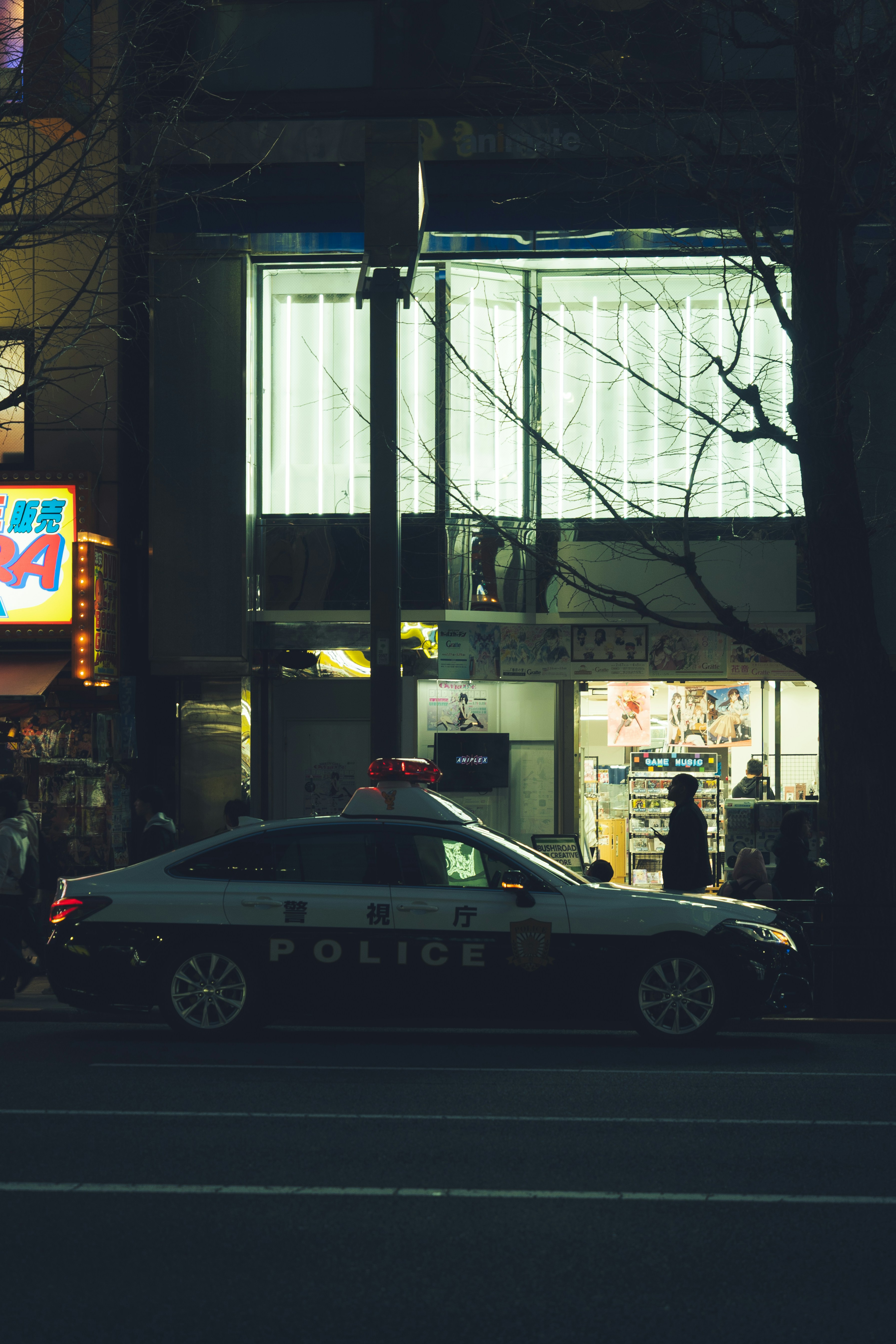 Night Patrol: A Tokyo Police Car Resting Under Neon Shopfront