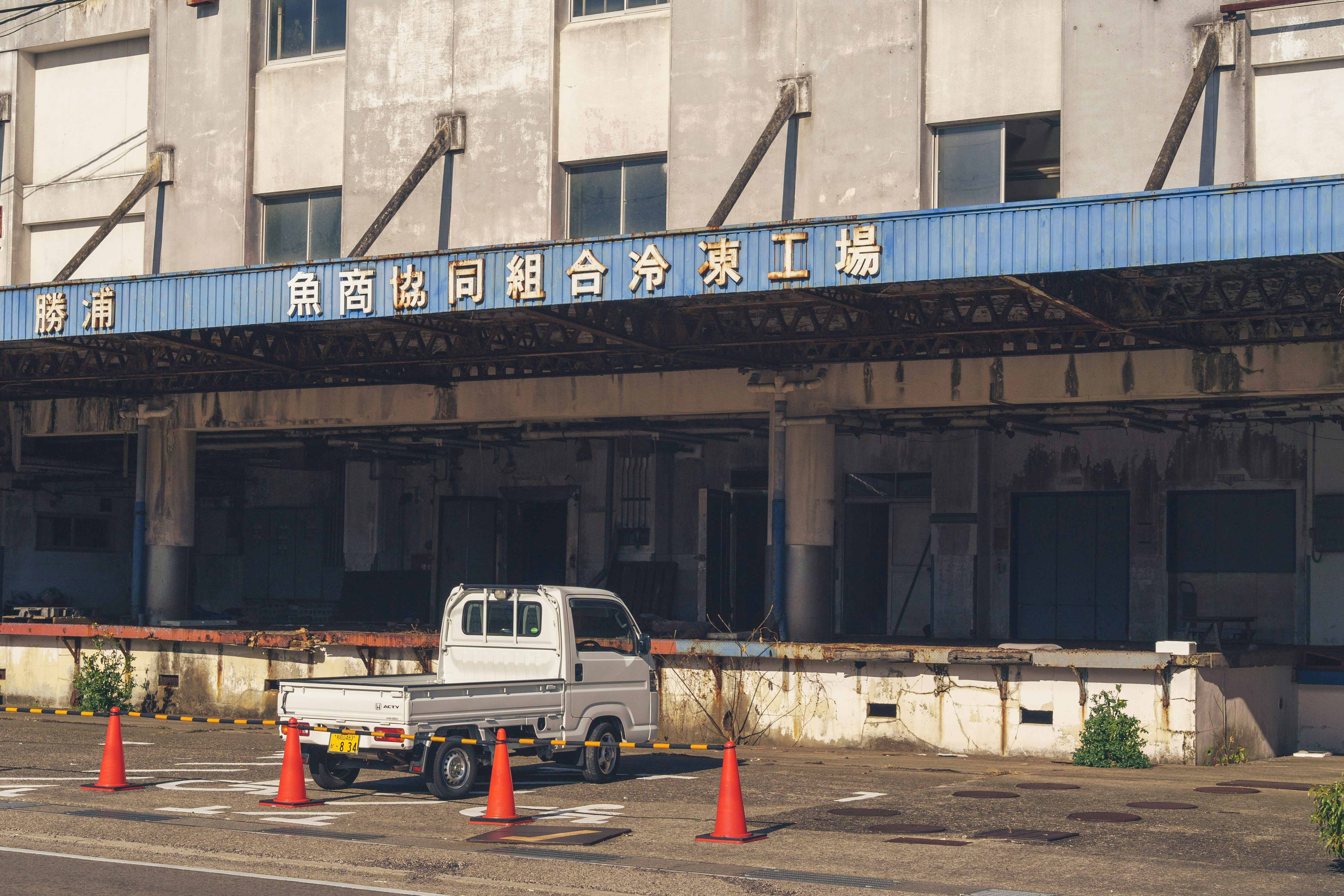 Abandoned Warehouse Lot with a Small White Truck and Orange Traffic Cones