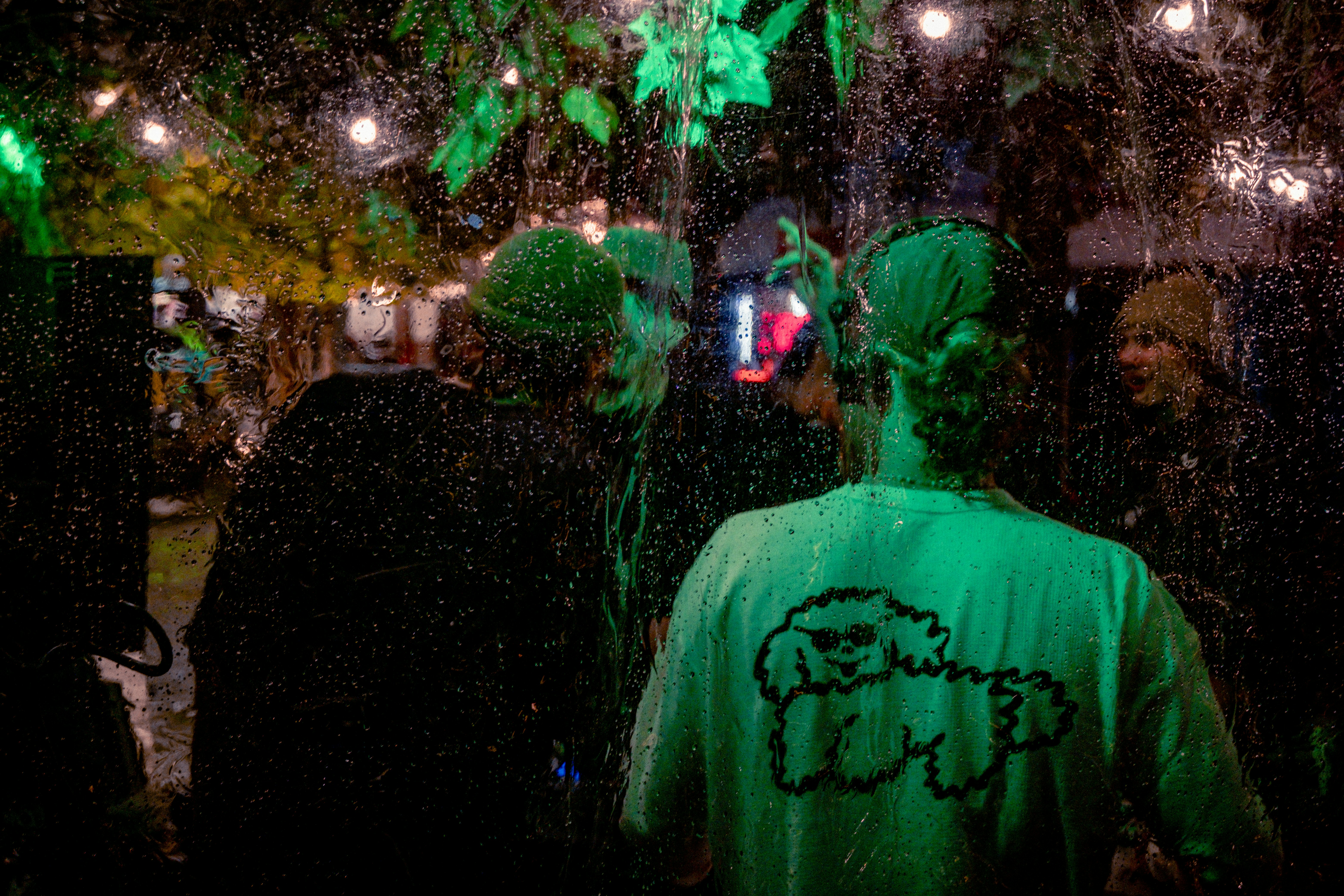 Green-lit Crowd Through Rainy Glass