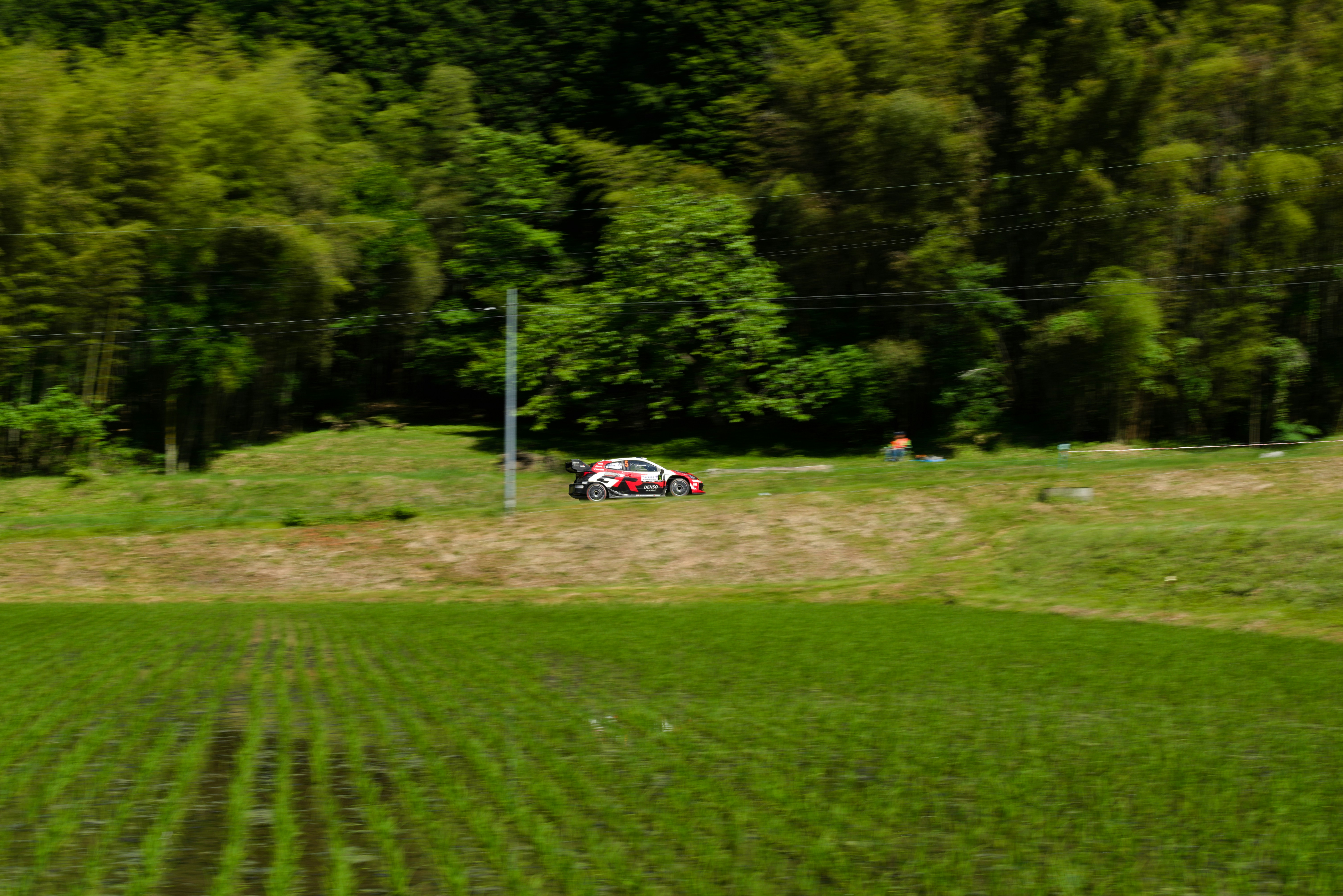 Dusty Rally Break: A Tiny Red Car on the Open Track