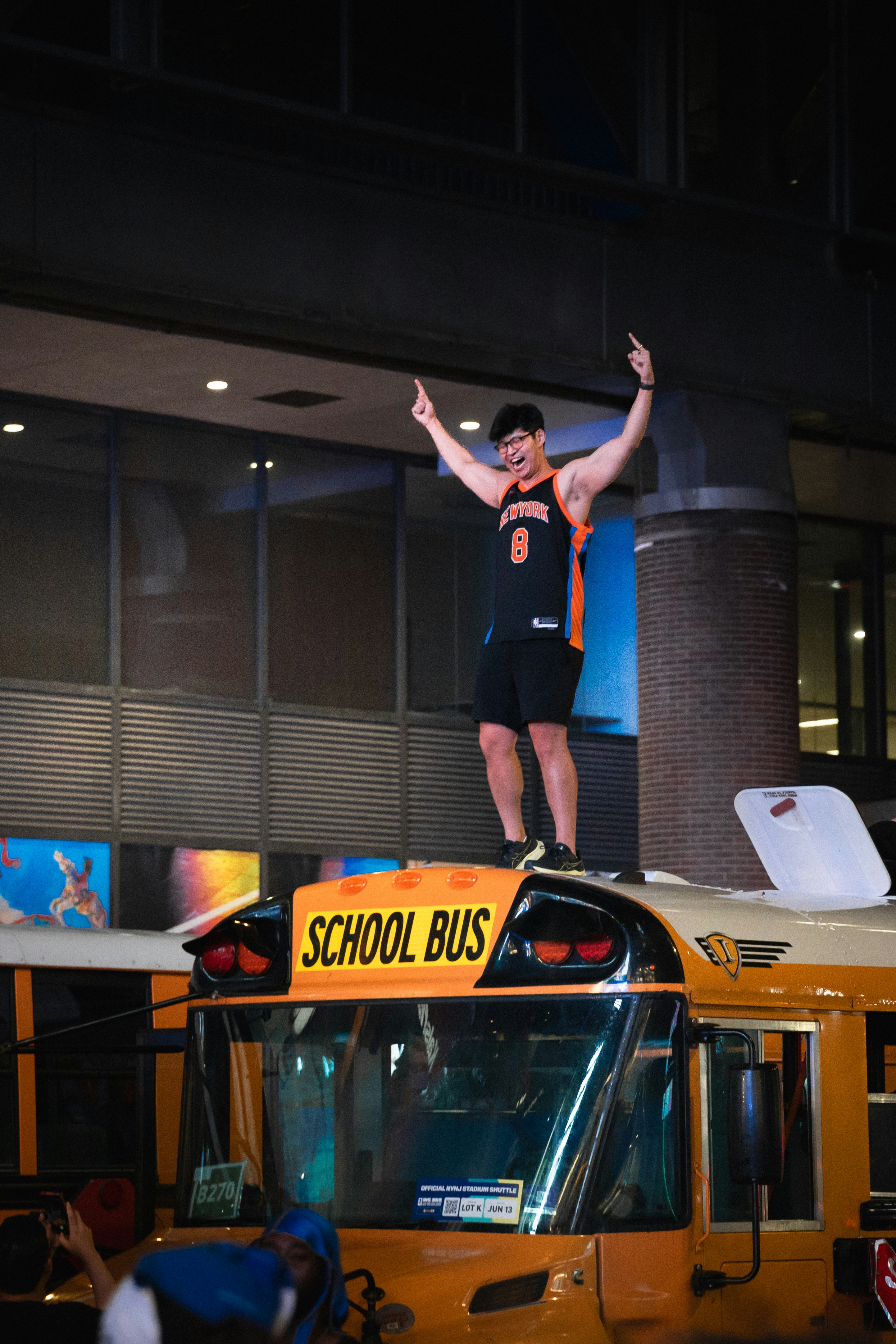 Victory Stance on a Yellow Parade: Student Athlete on the Bus Roof