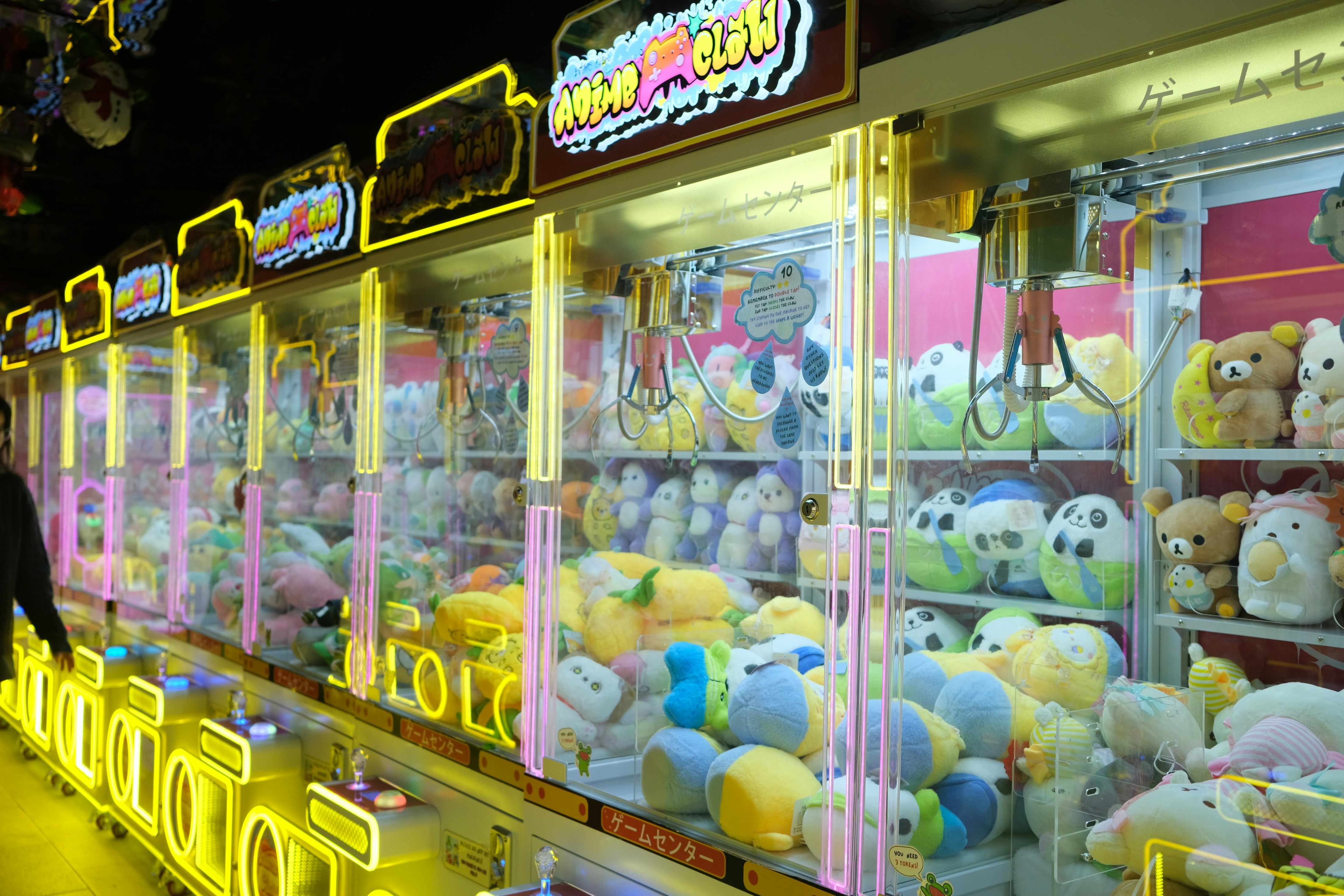 Brightly lit claw machines filled with colorful plush toys.