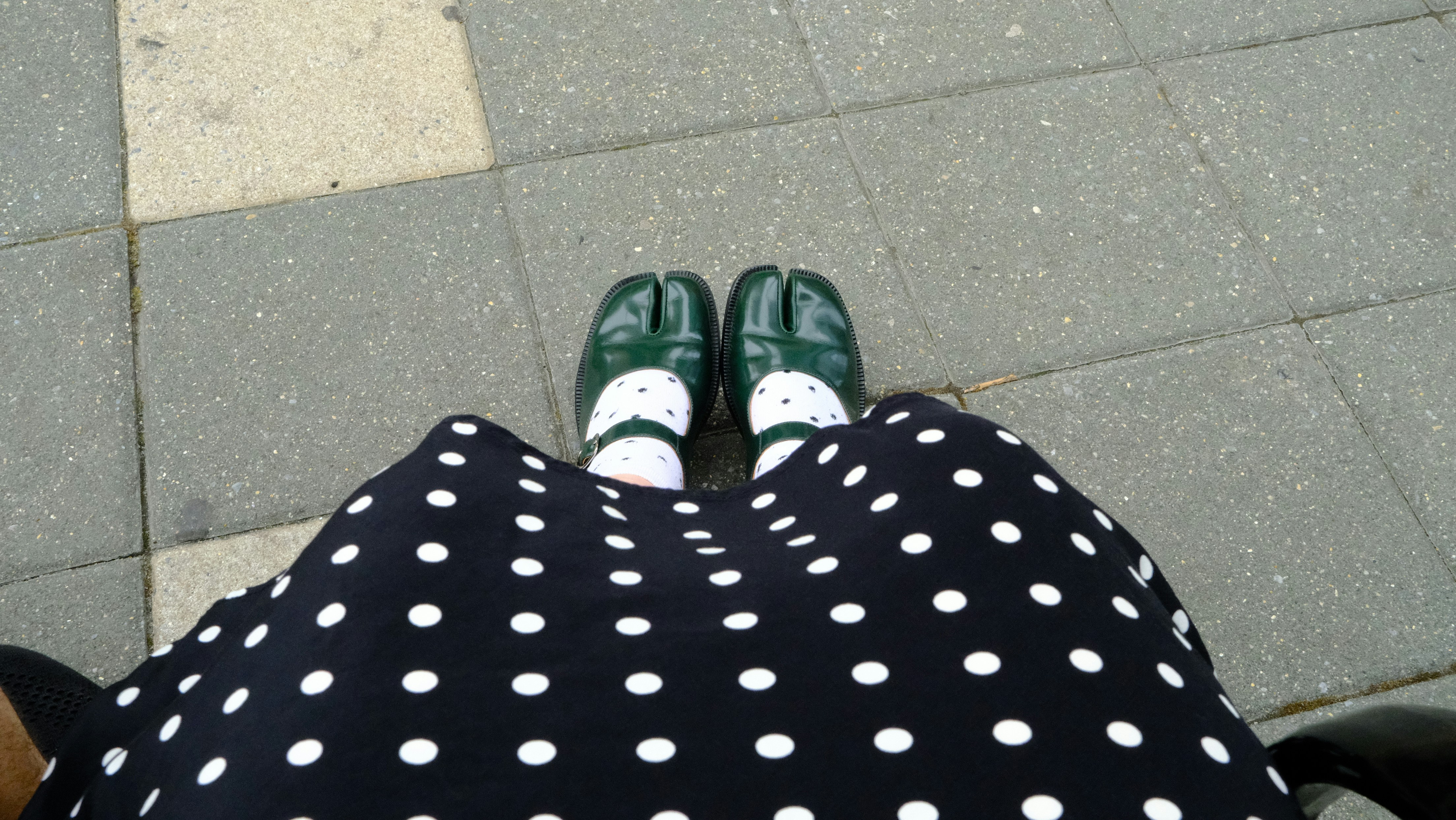 Polished Steps: Green Shoes and Polka-Dotted Skirt on Urban Tiles