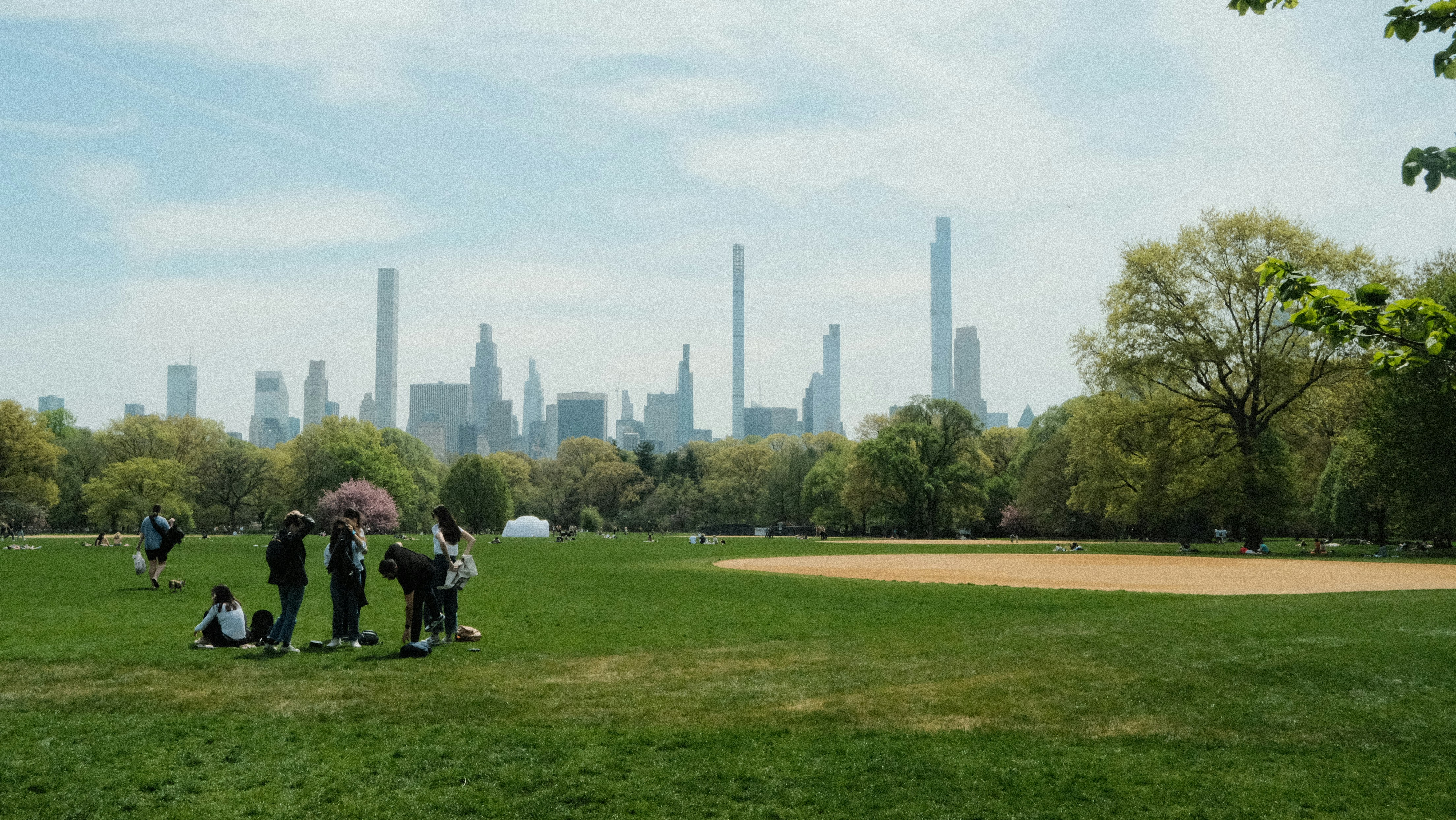 City skyline overlooks a green park with people.
