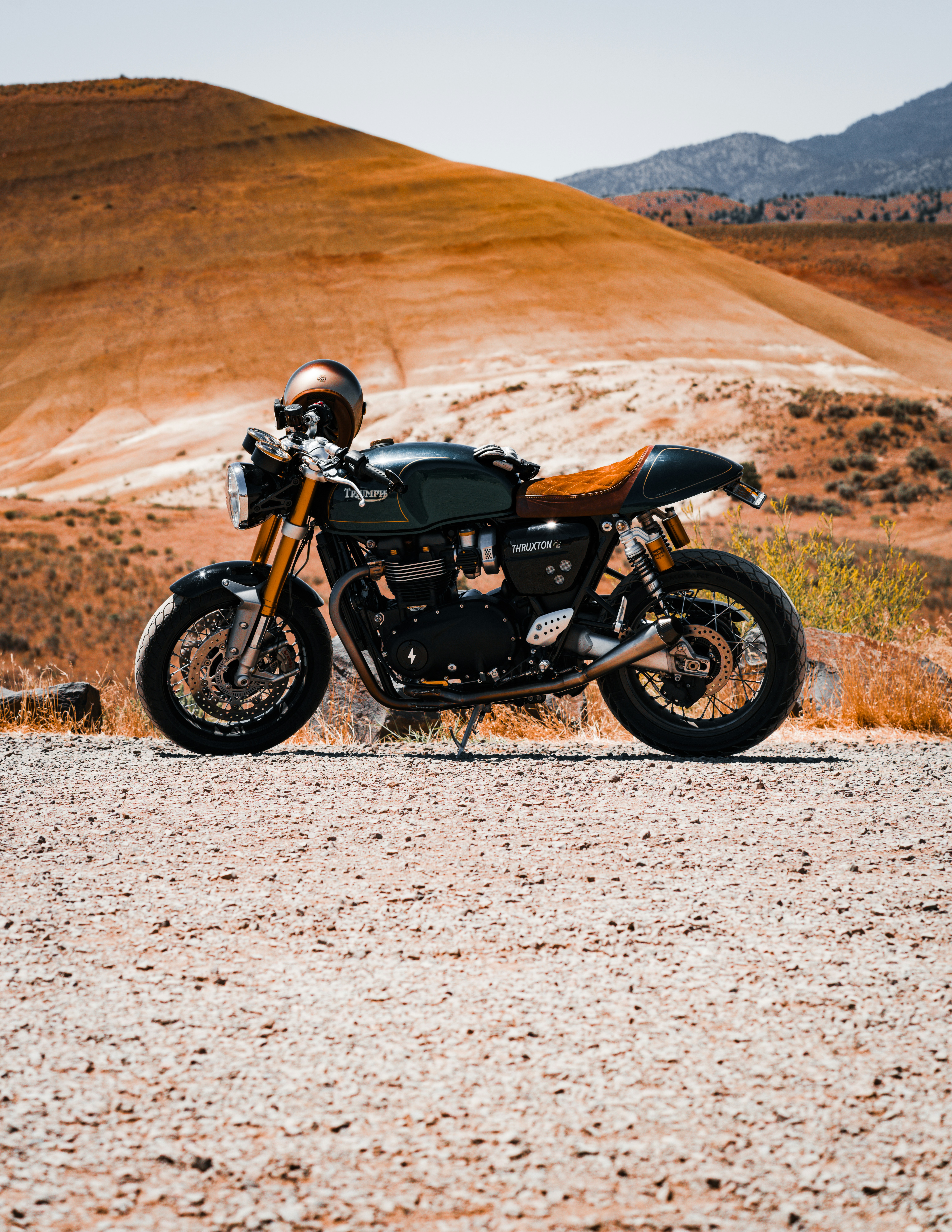 Desert Thunder: A Triumph motorcycle resting against eroded clay hills