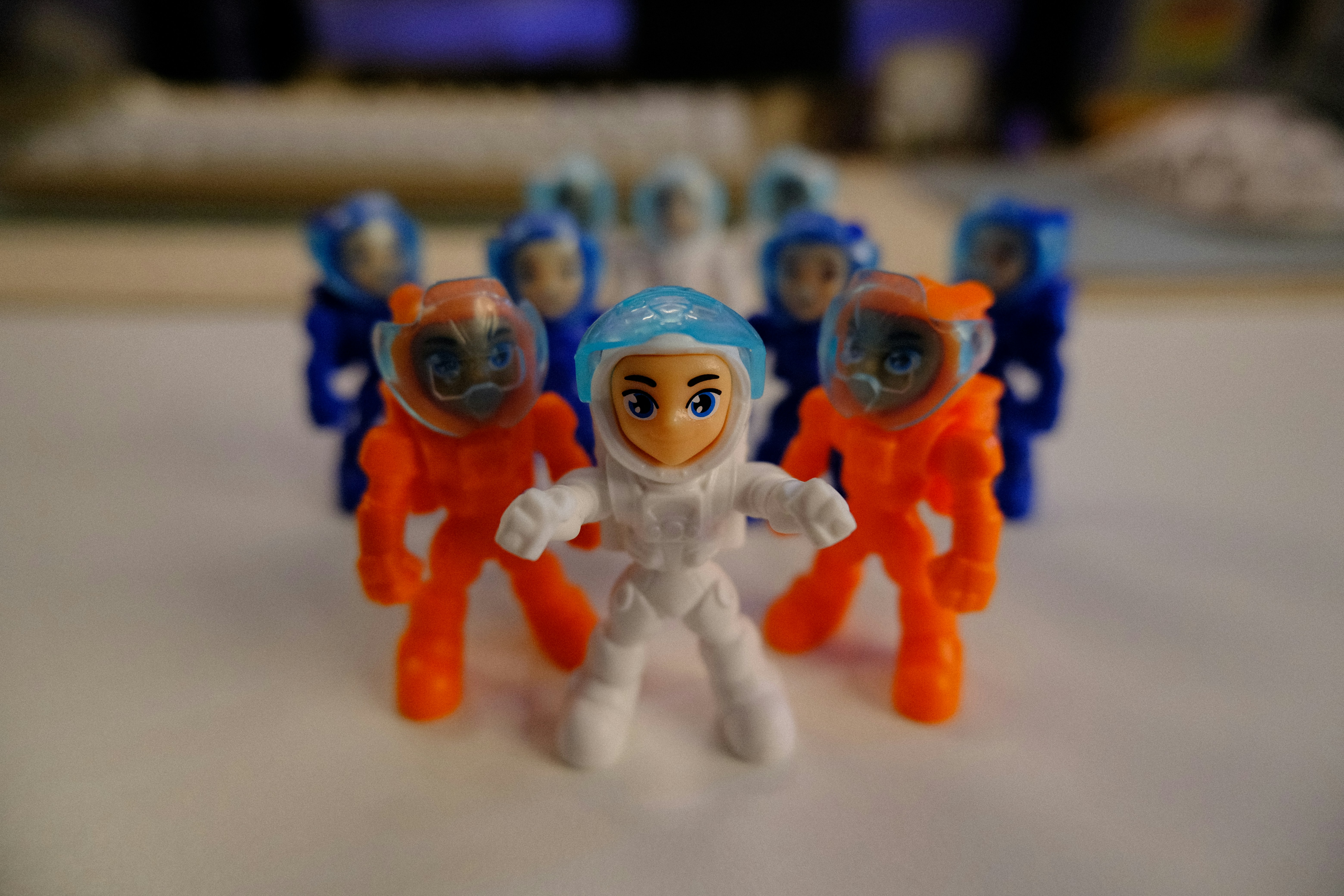 Colorful toy astronaut figures standing on a surface.
