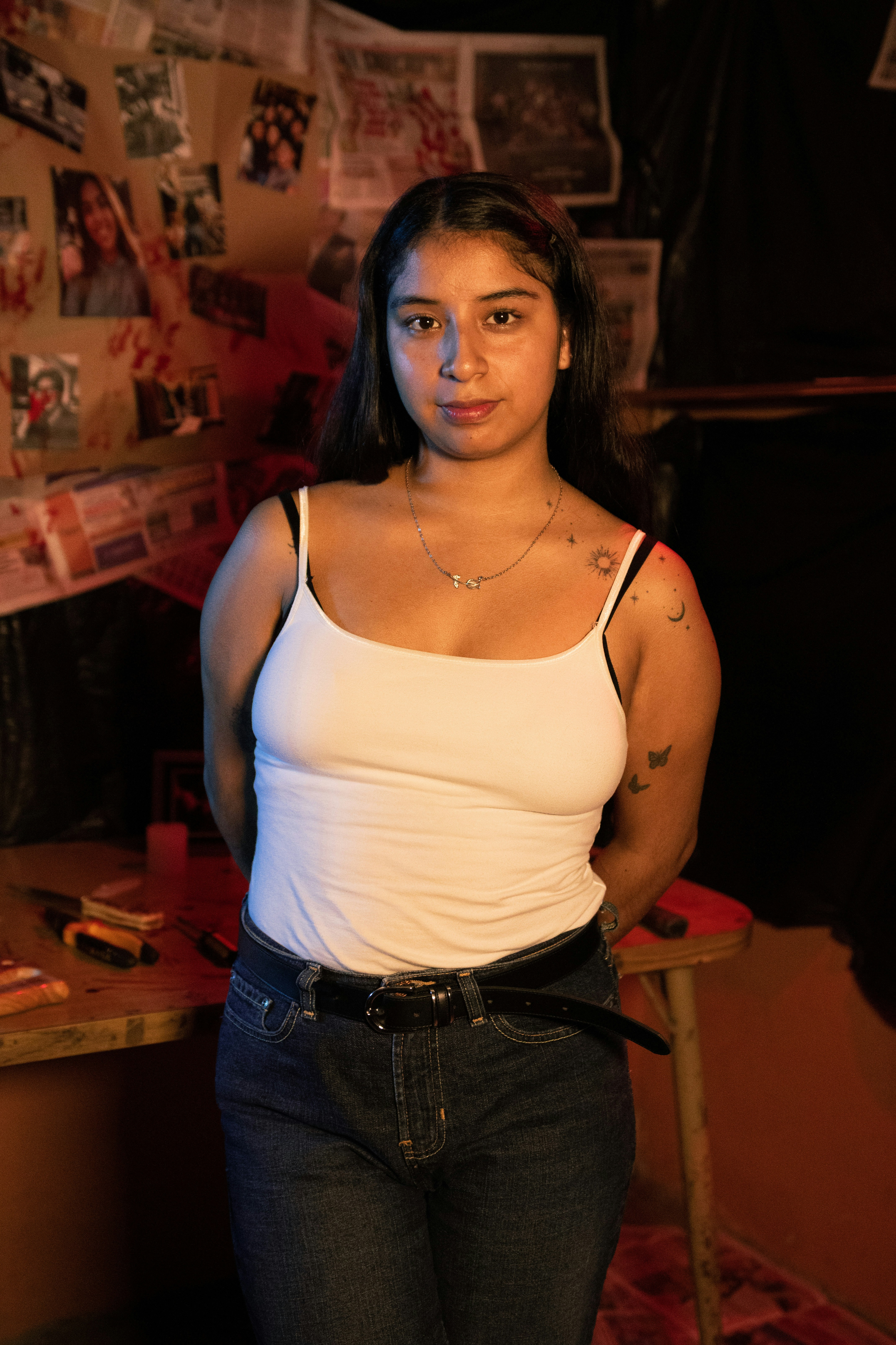 Woman in white top and jeans looking at camera.