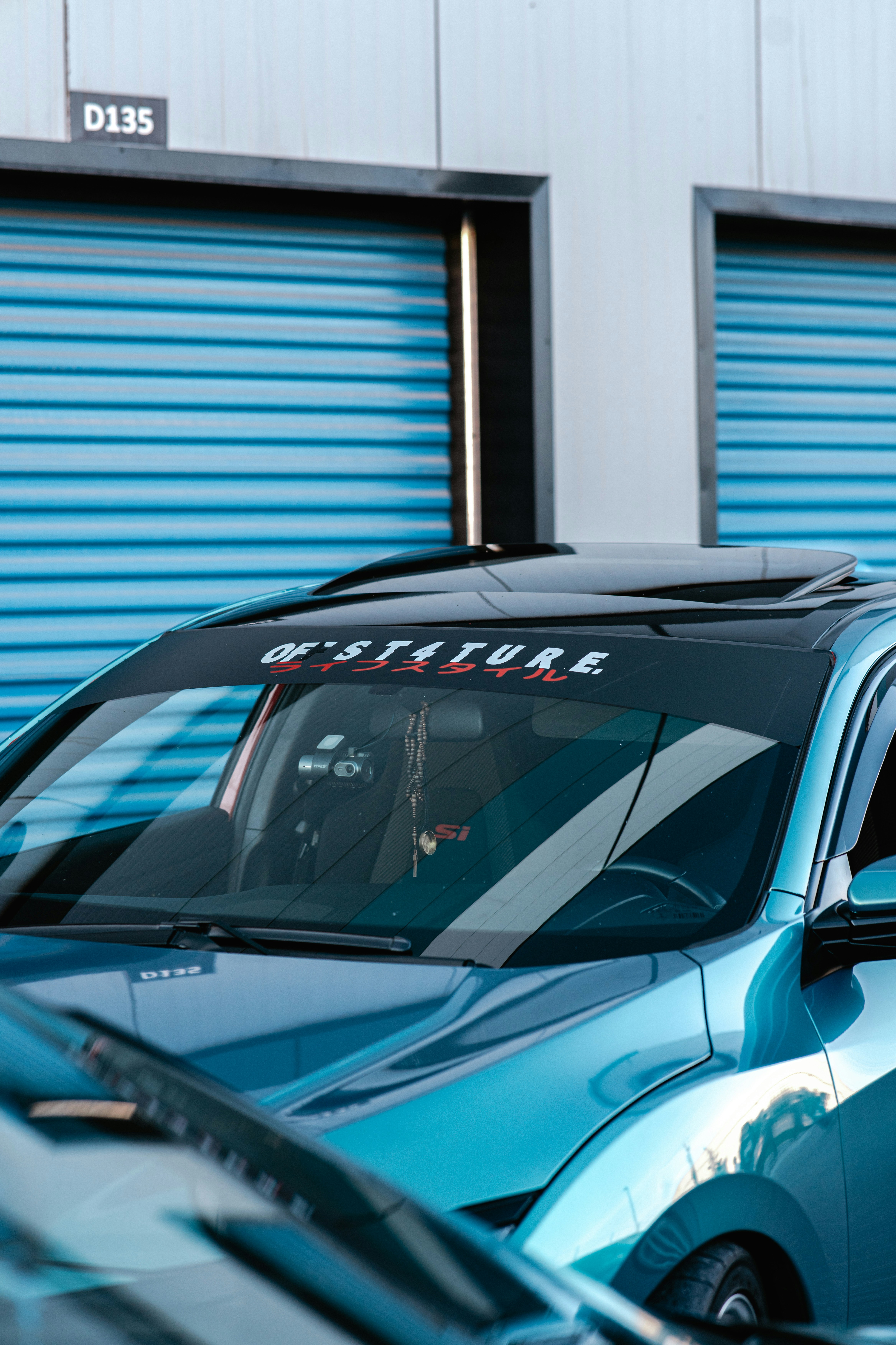 Blue van parked under corrugated steel; windscreen branding reads 'OFFATURE' as a custom wrap stands out