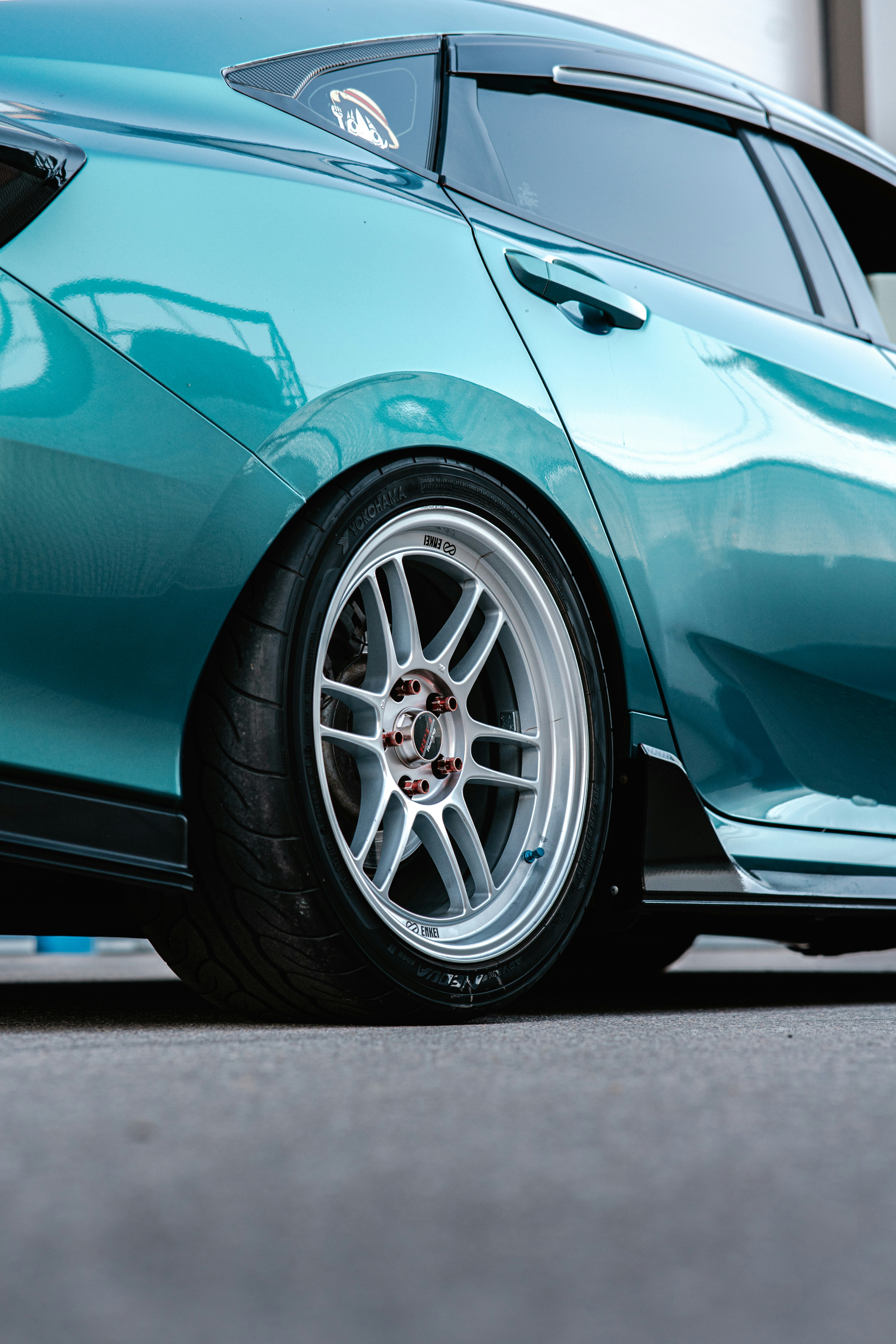 Azure Focus: A teal sports sedan and its sun-kissed wheel frame