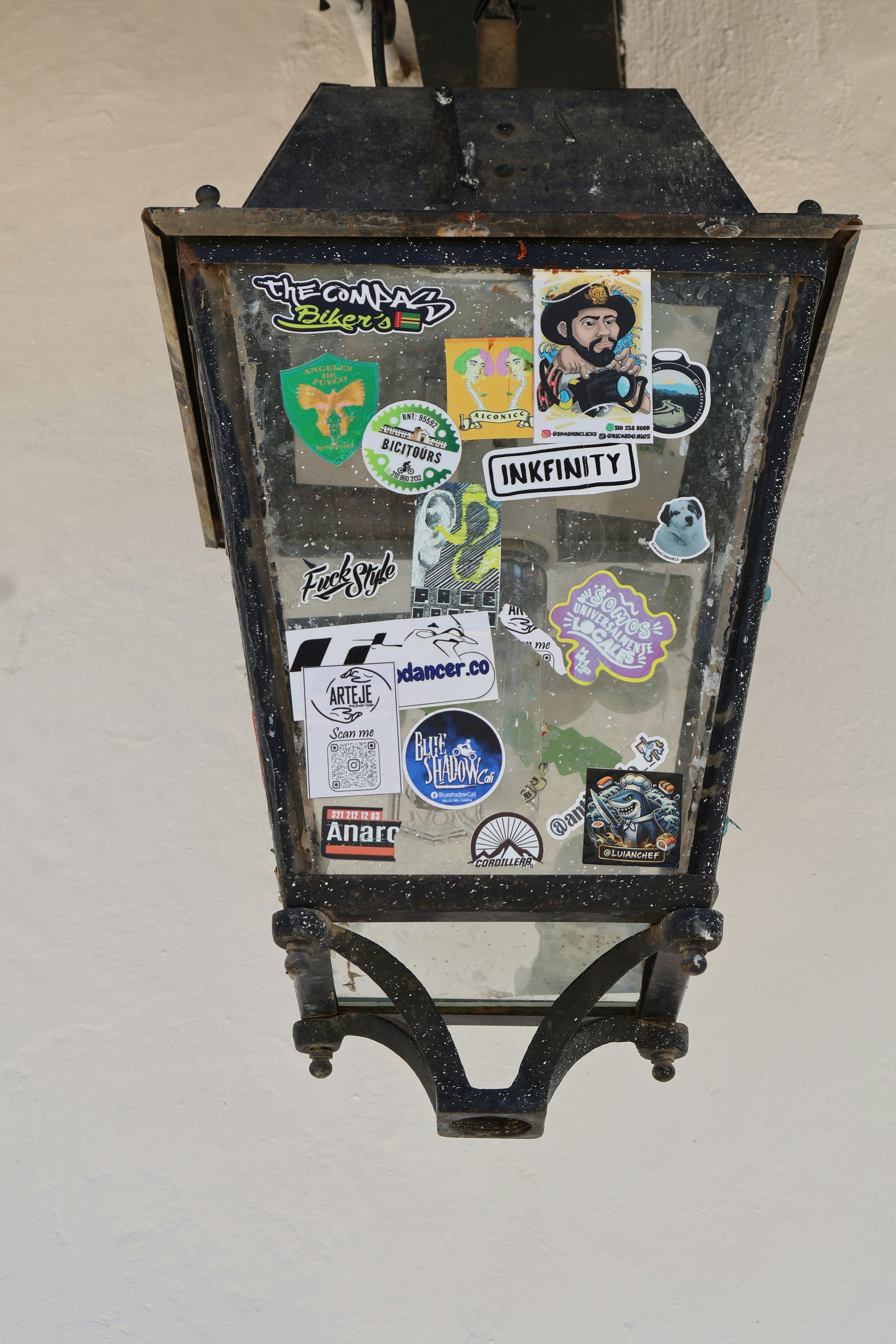 An old street lamp covered with many colorful stickers.