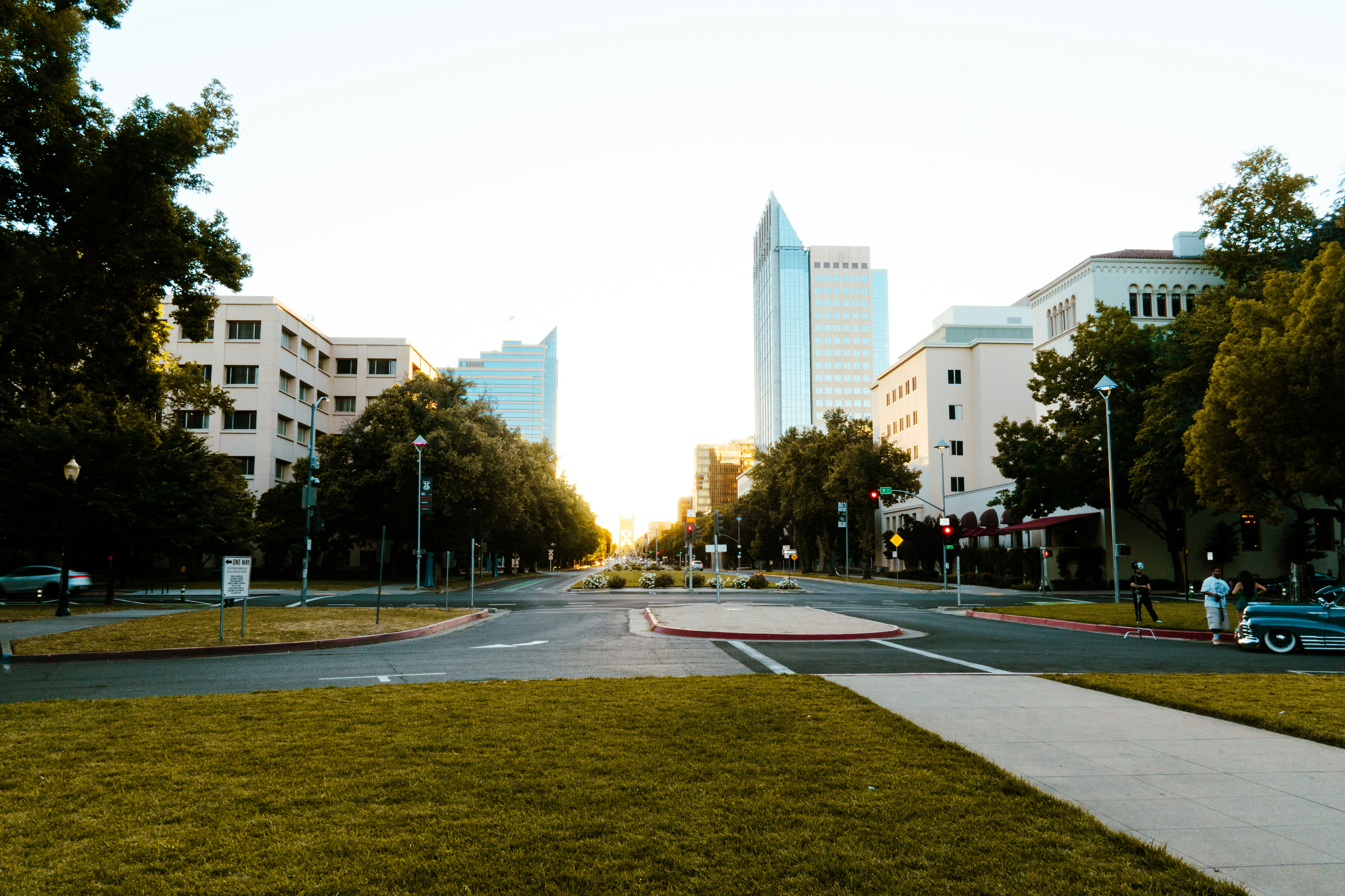 A wide city street with buildings and trees at sunset.
