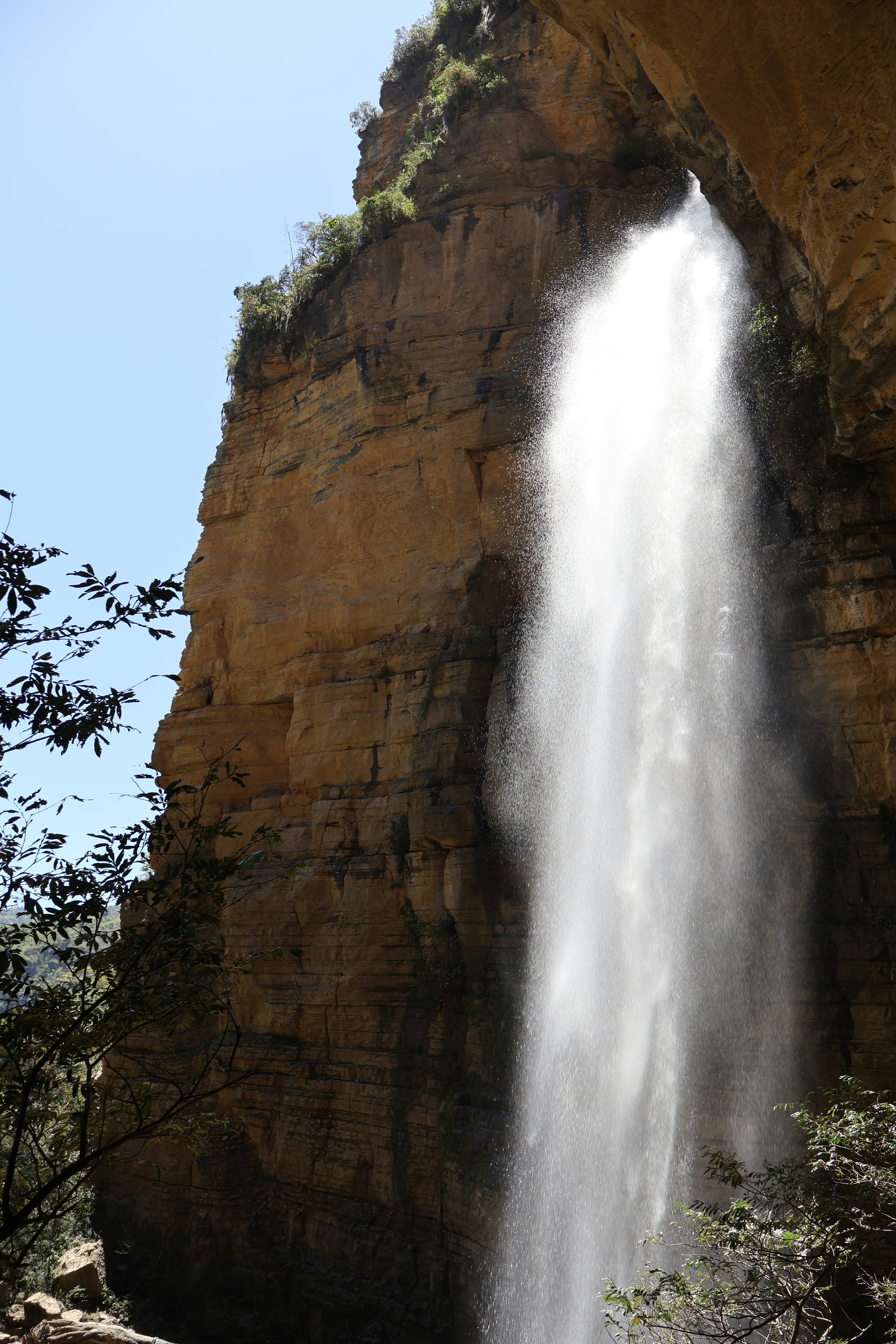 Cascading Whisper: A Narrow Waterfall Between Cliff Faces