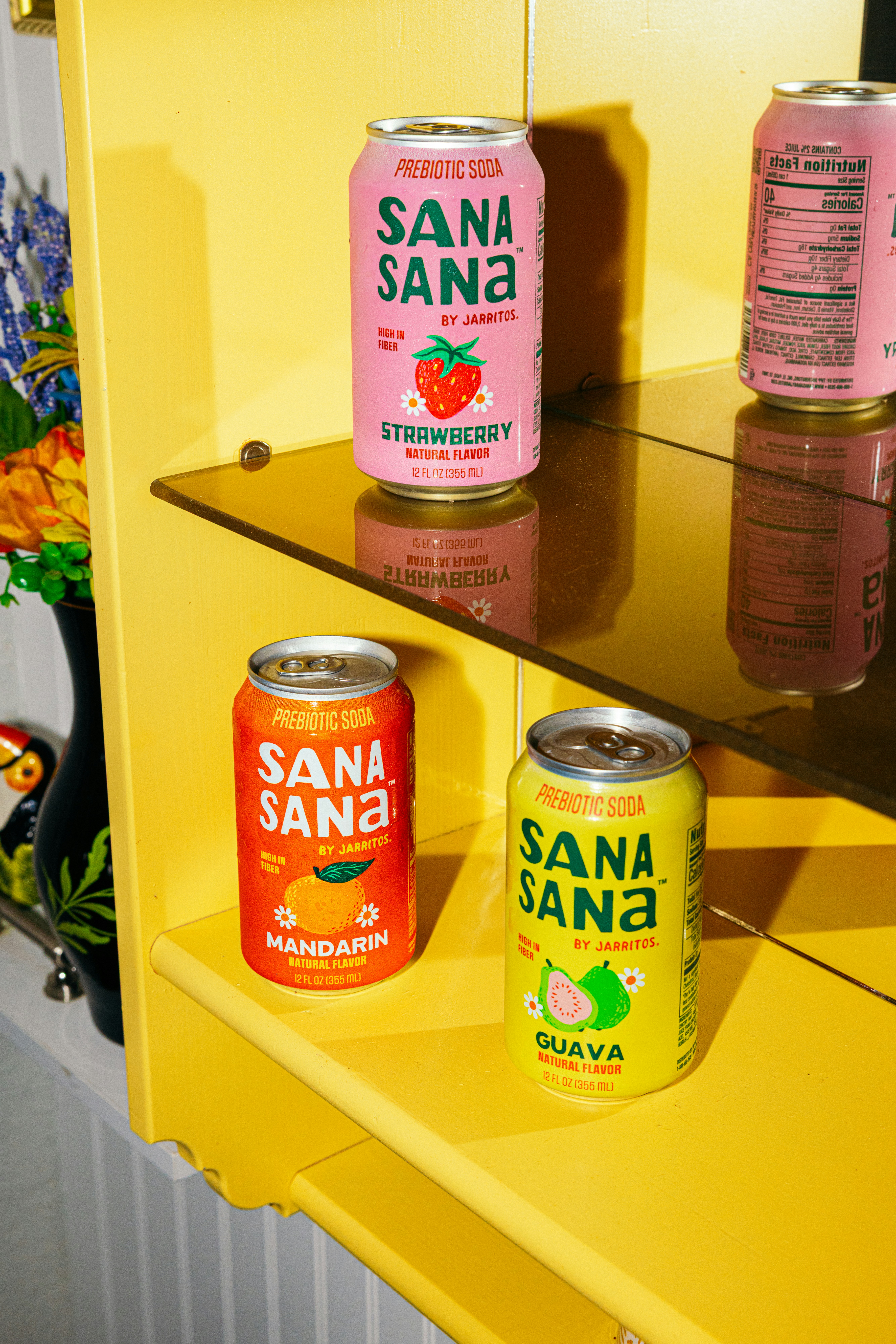 Sugary Spotlight: Trio of Sana Sana Cans on a Bright Yellow Shelf