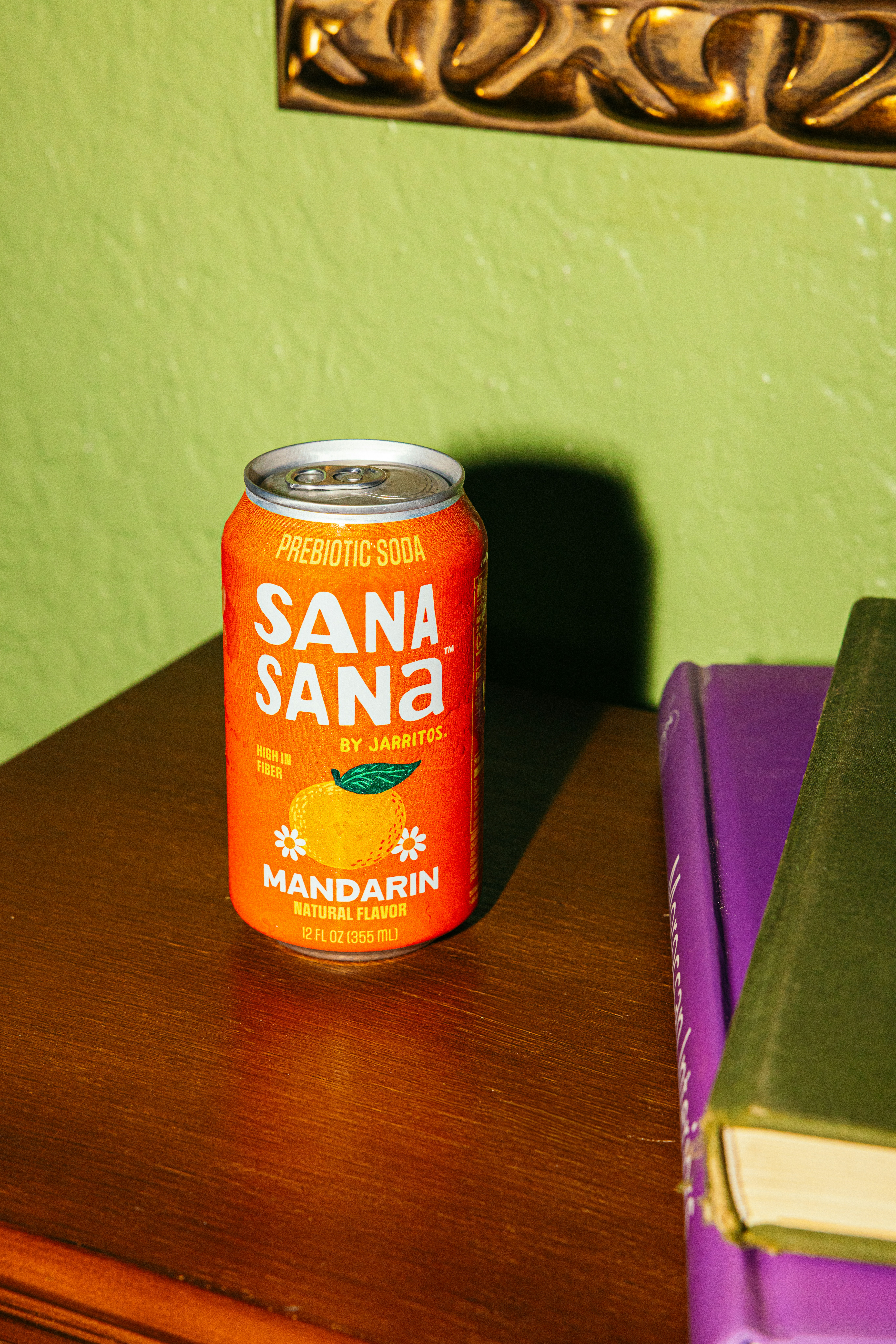 Orange Soda Can on a Wooden Desk with a Purple Book