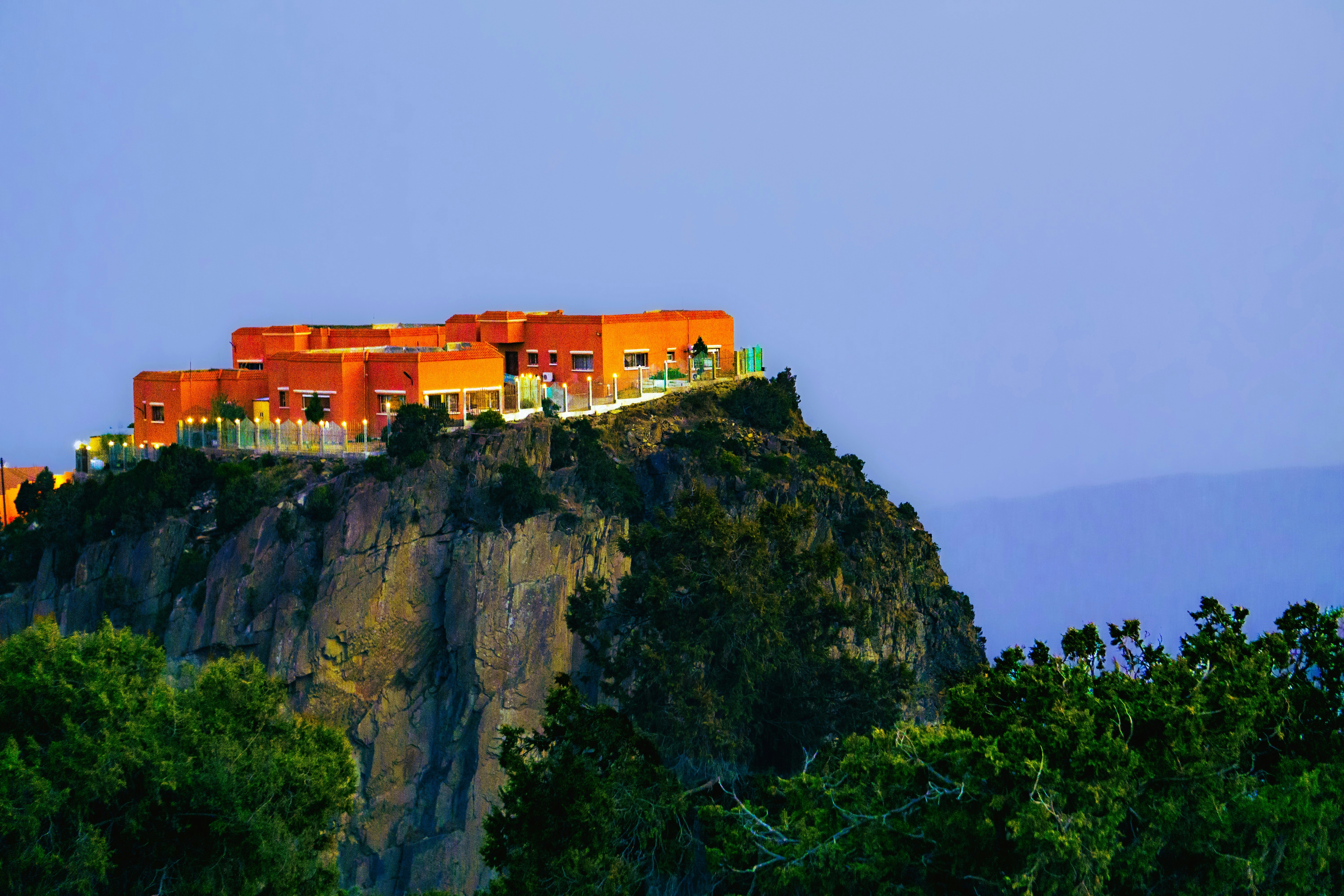 Red-Orange Clifftop Complex Overlooking Verdant Trees