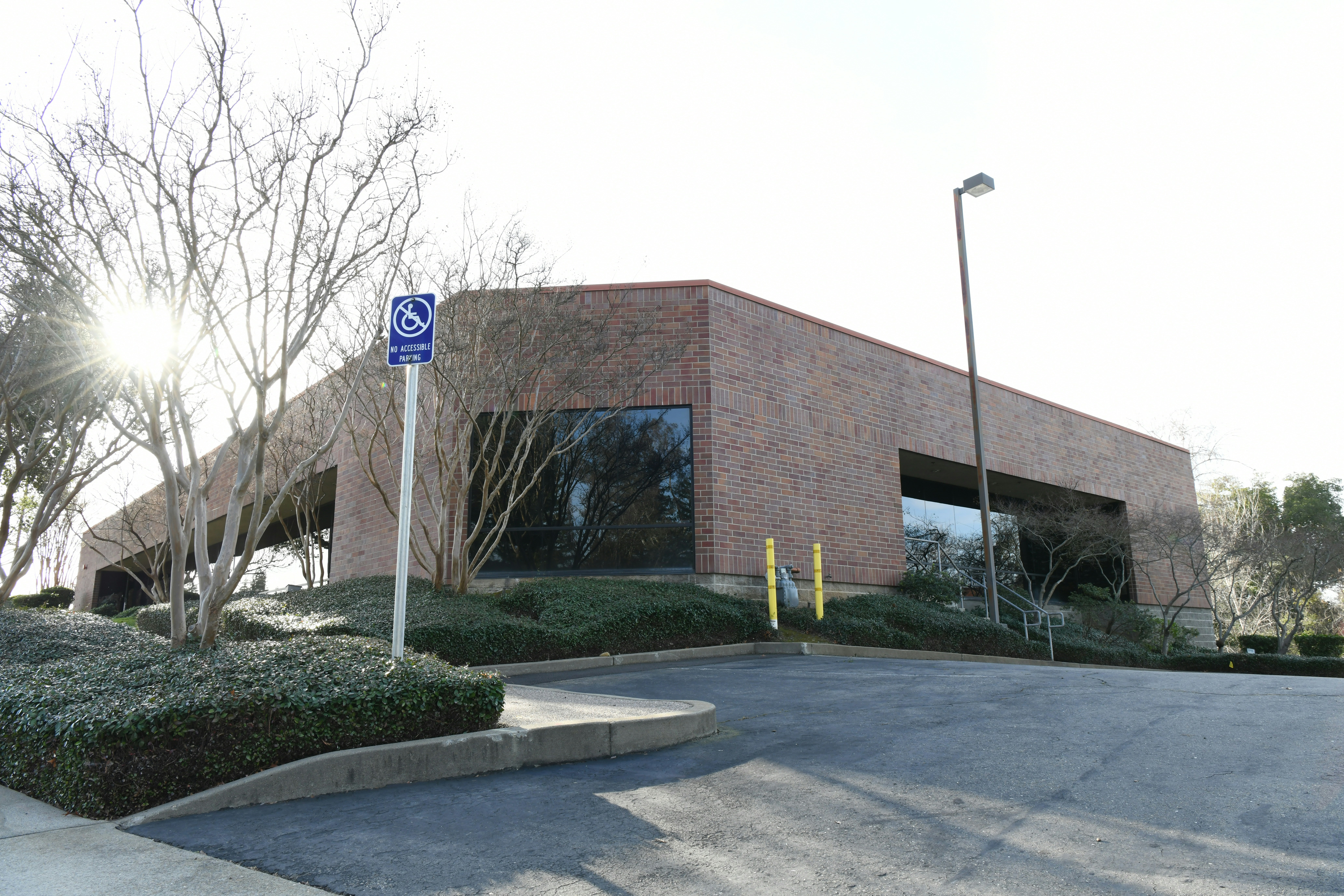 Sunlit Campus Building Emerges from Quiet Parking Lot
