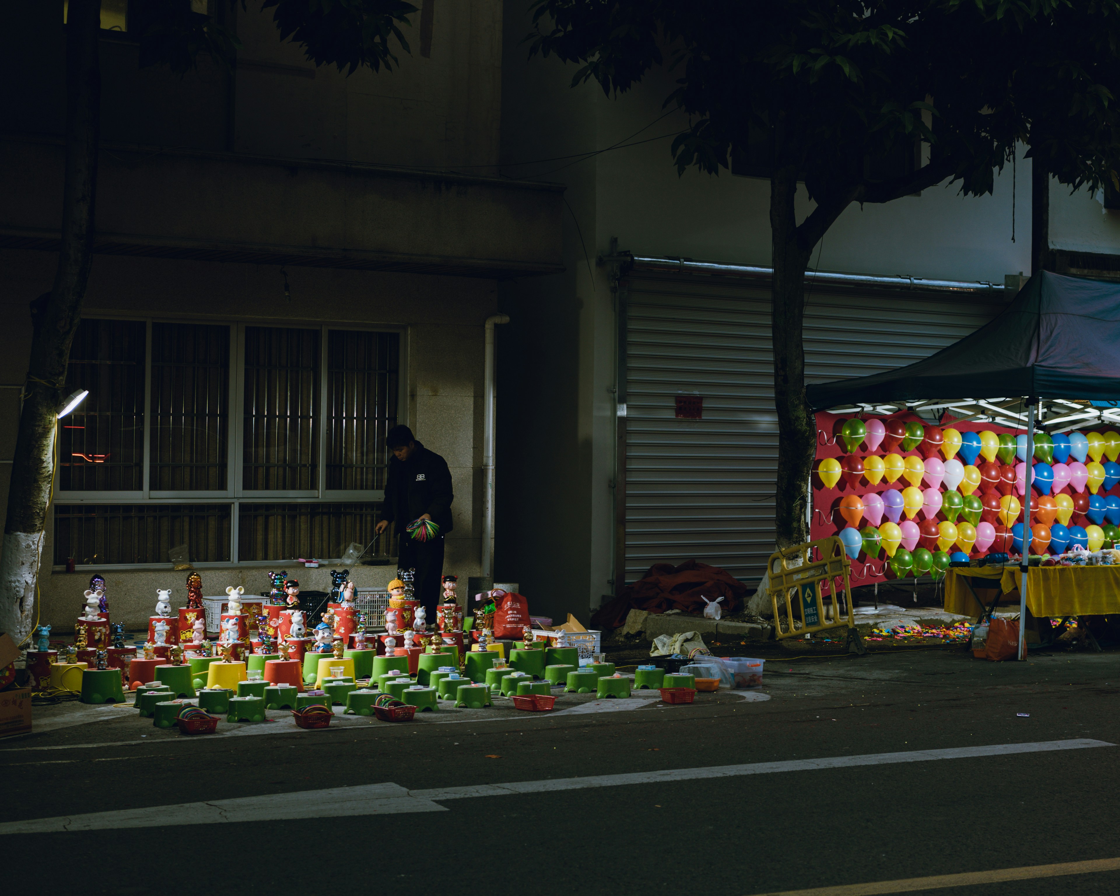 Street Market at Dusk: Toys and Balloons Under a Flickering Streetlight