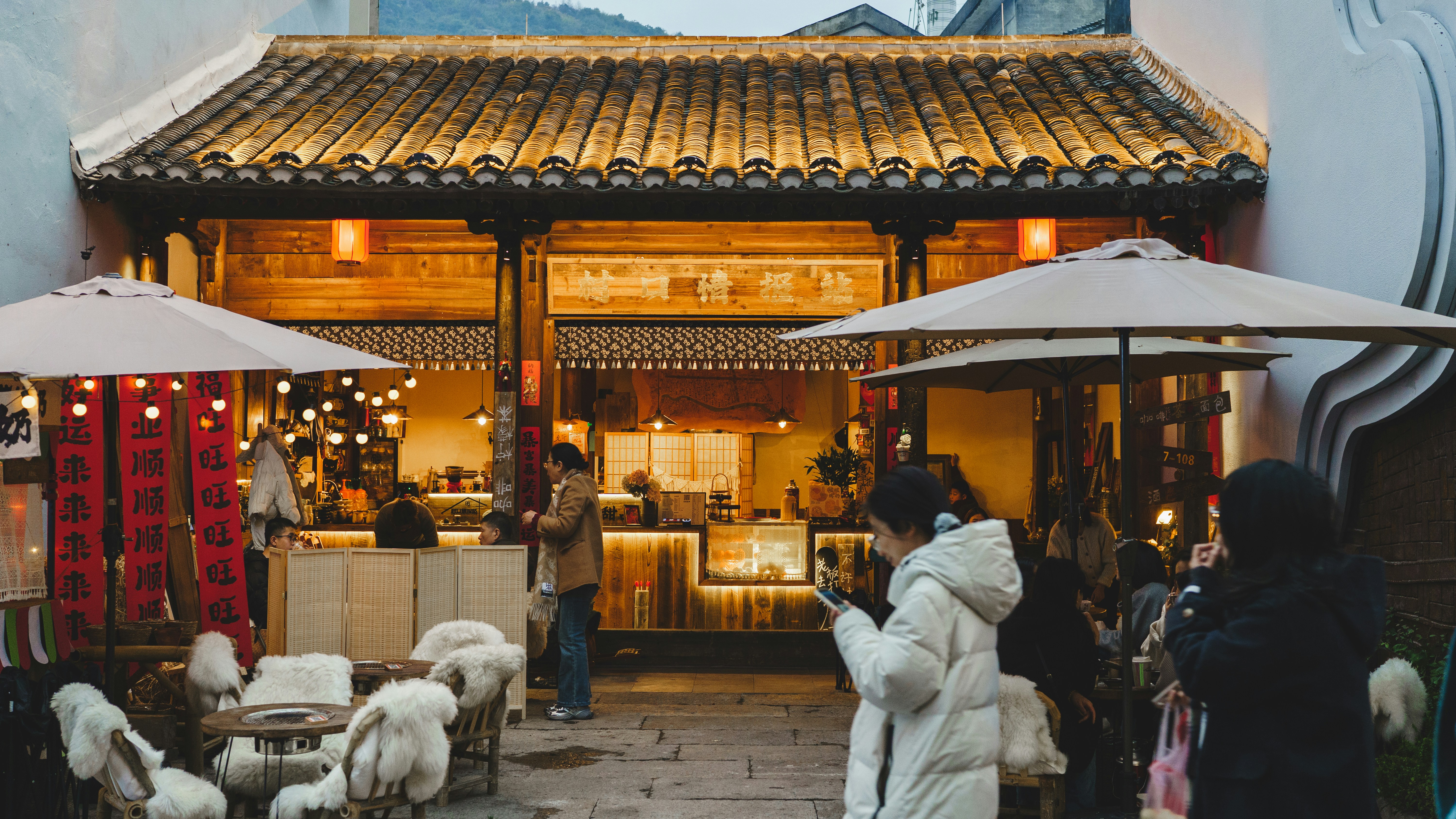 Illuminated traditional building with outdoor cafe seating and patrons.