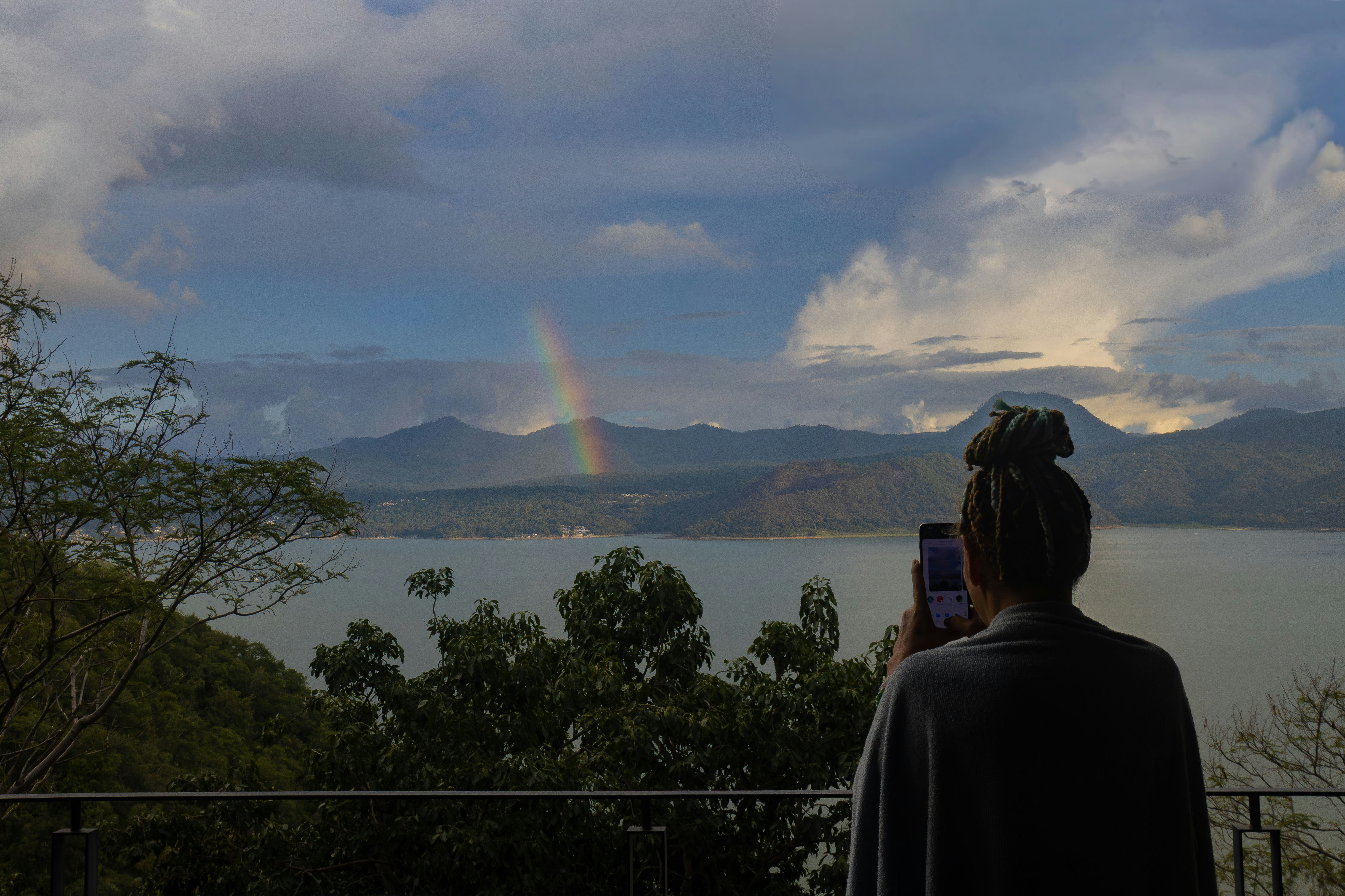 Portrait at the overlook: a lone observer framing the rainbow