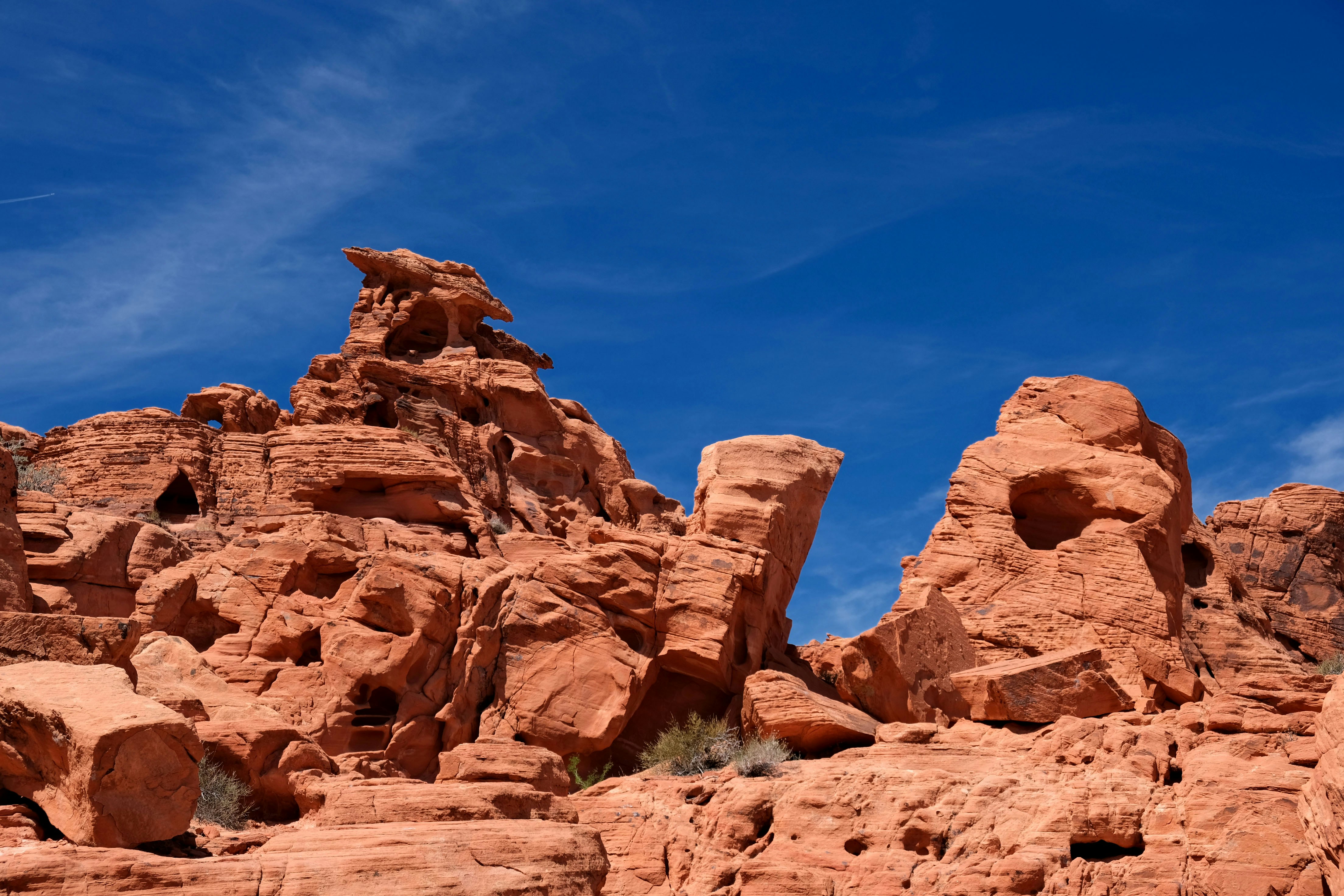 Vast red rock formations rise beneath a deep blue sky, with sculpted arches and weathered pillars forming a rugged desert landscape.