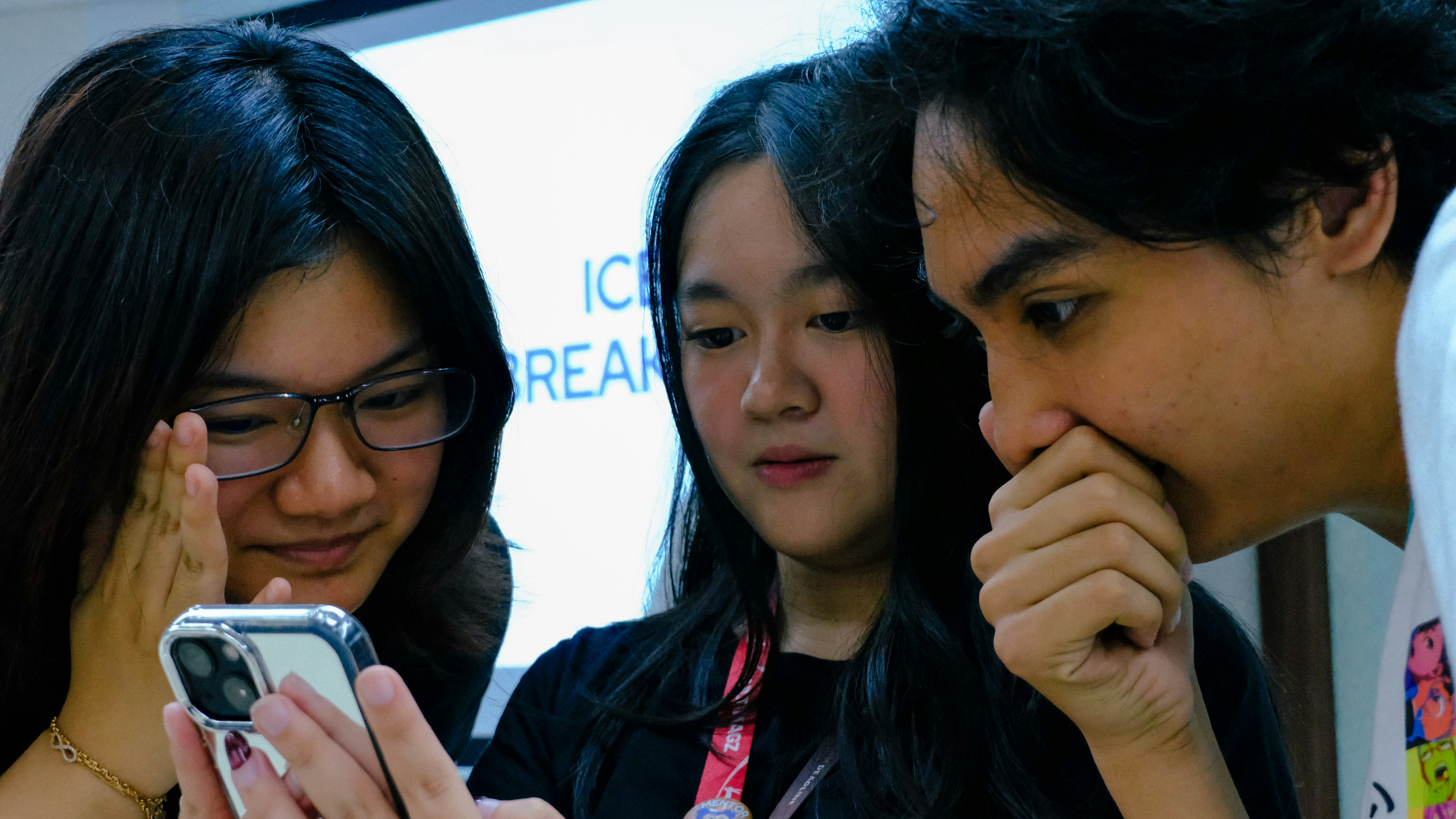 Young adults focused on a smartphone screen.
