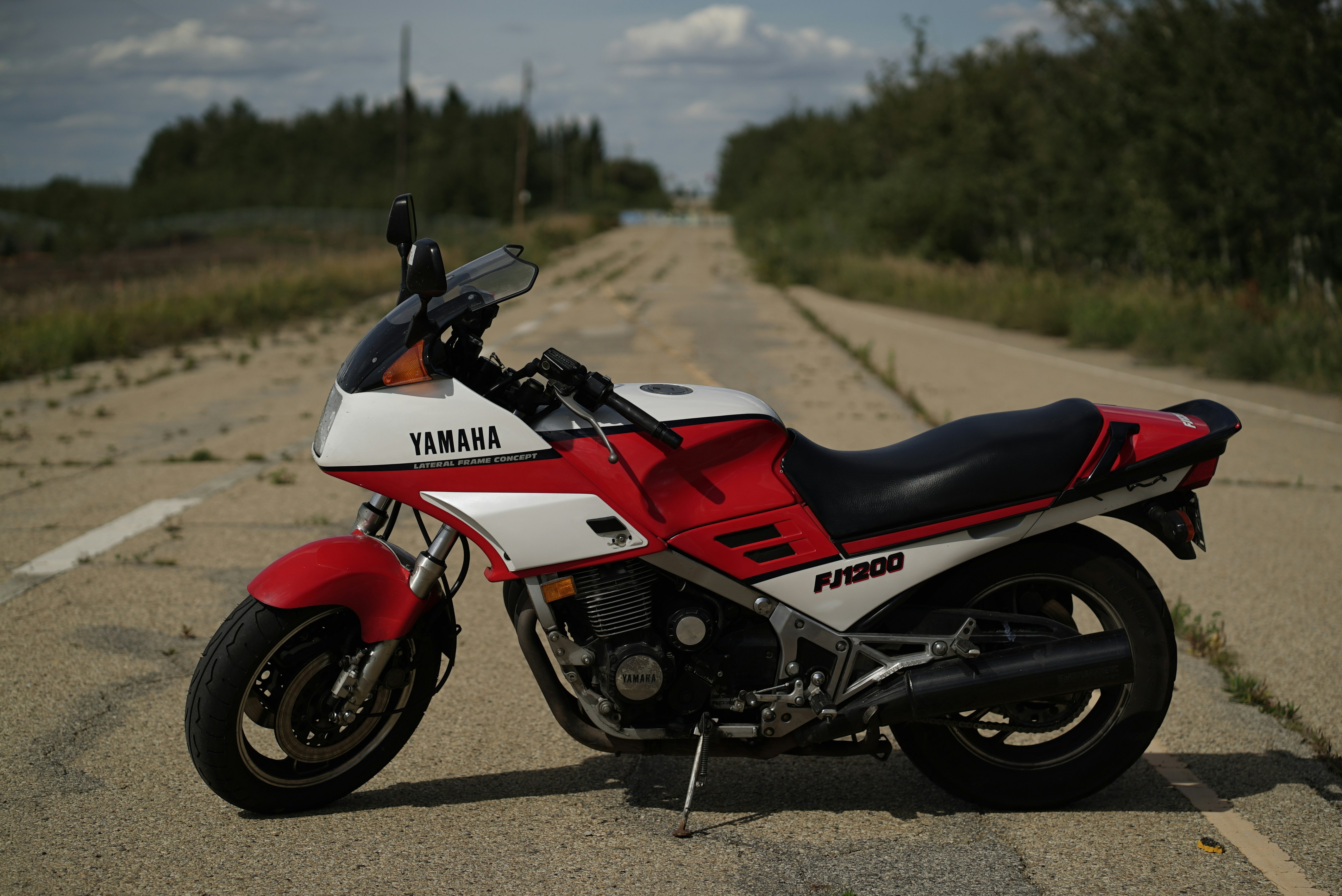 Red and white Yamaha FZR motorcycle resting on an abandoned road