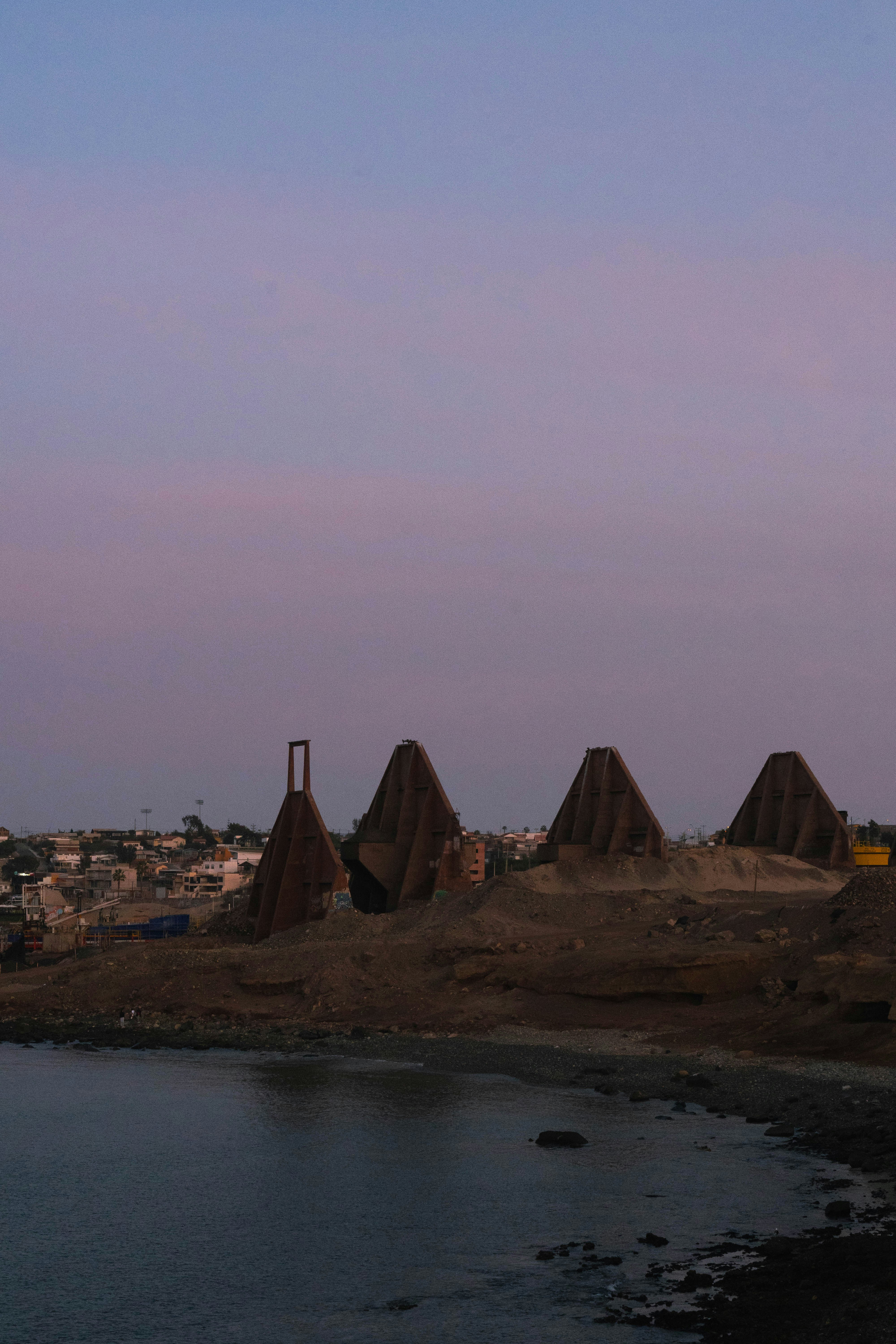 Silhouette of coastal structures at dusk by the harbor