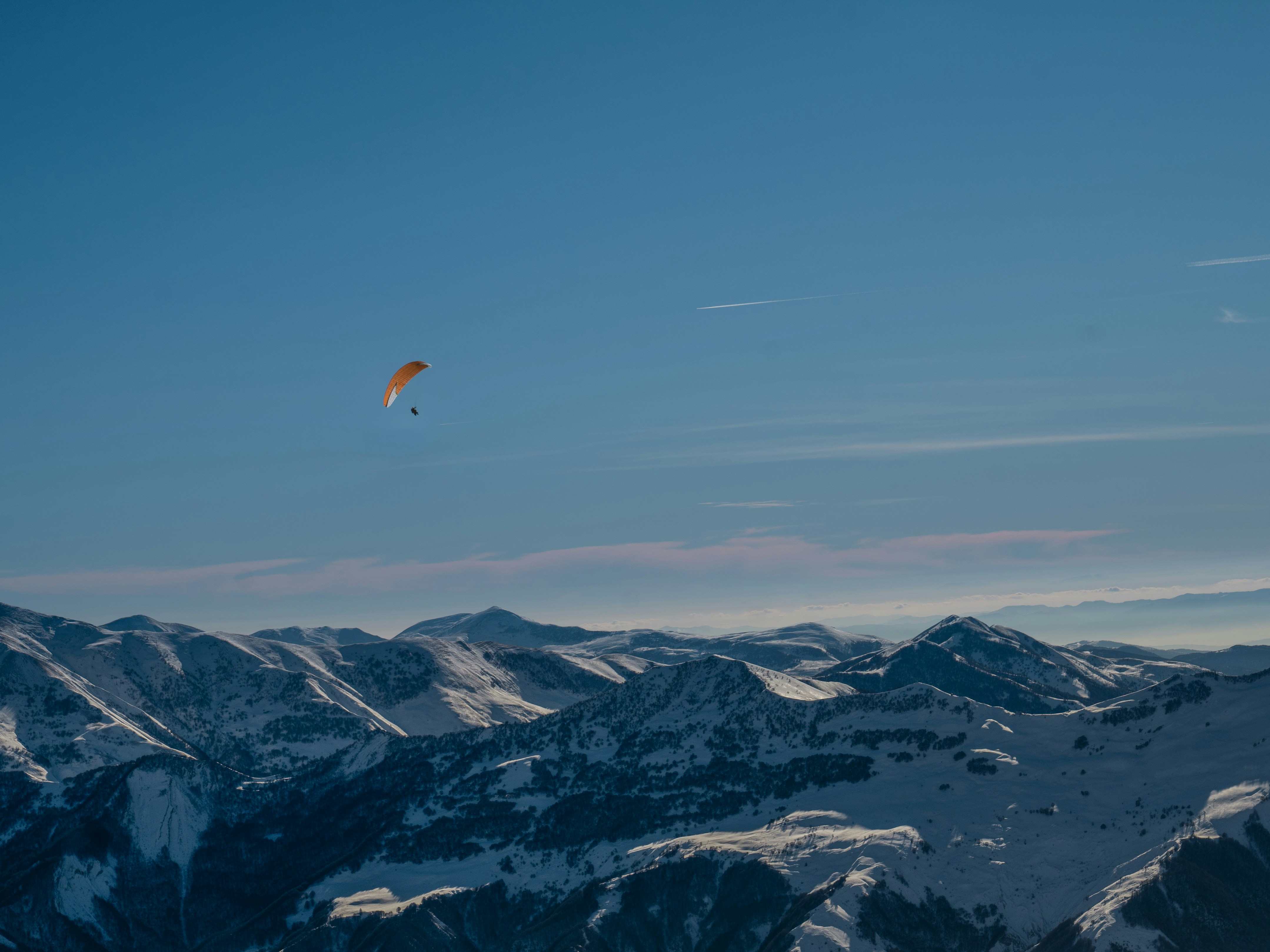 A Solitary Paraglider Over Alpine Crest at Dusk